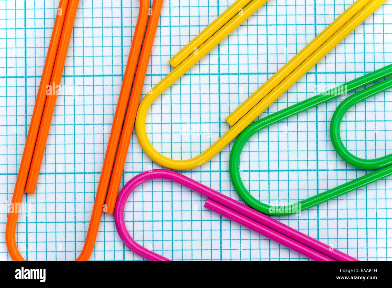 Giant paper clips arranged on a graph paper background Stock Photo - Alamy