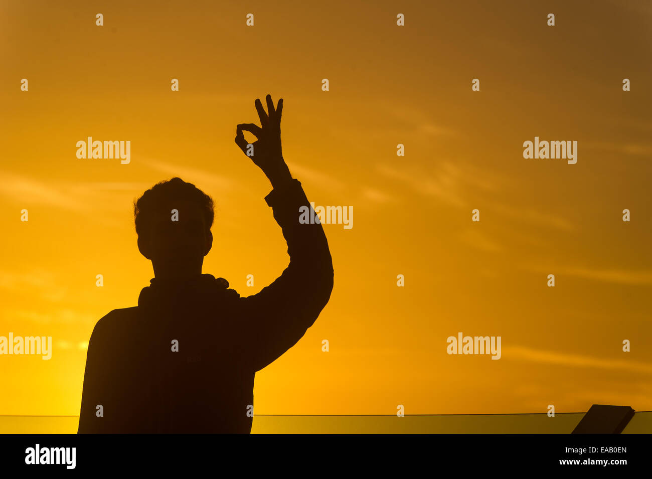 Silhouette of a man at sunrise giving an "OK" hand sign Stock Photo - Alamy