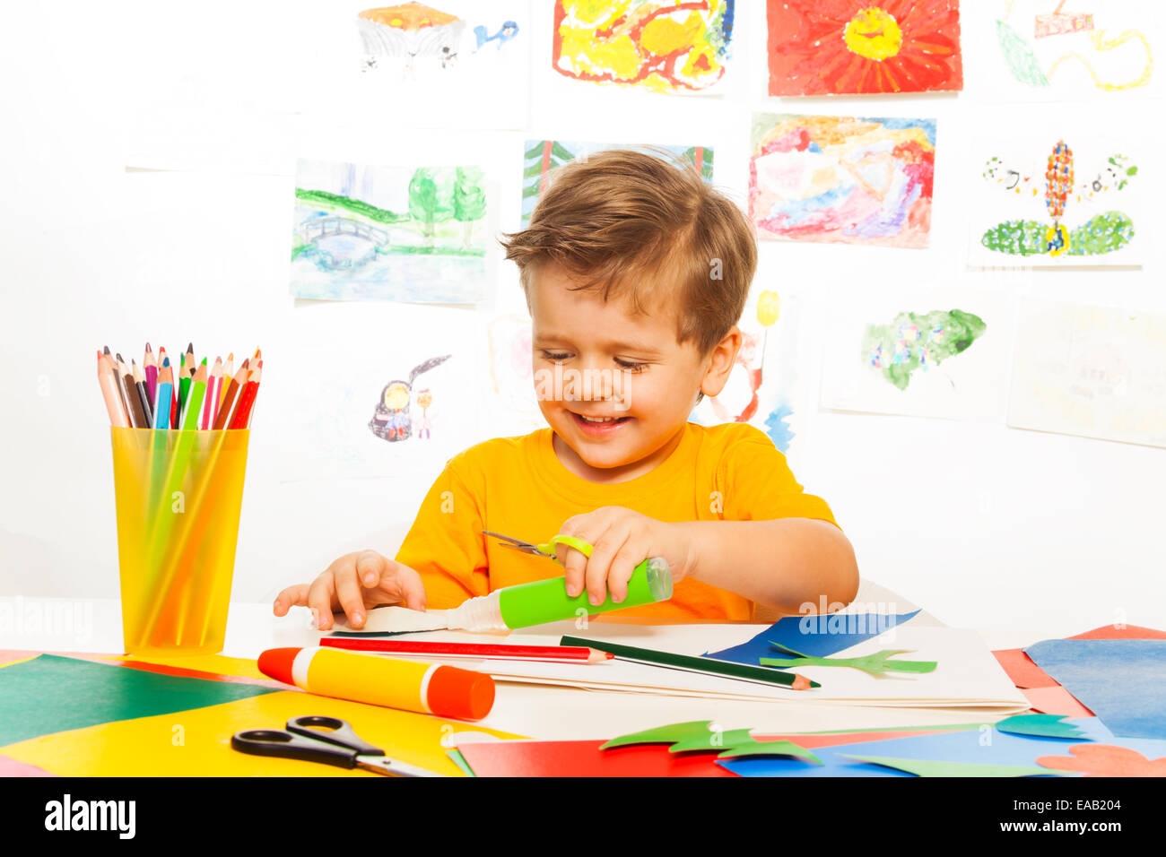 Happy small boy crafts with scissors, paper, glue Stock Photo - Alamy