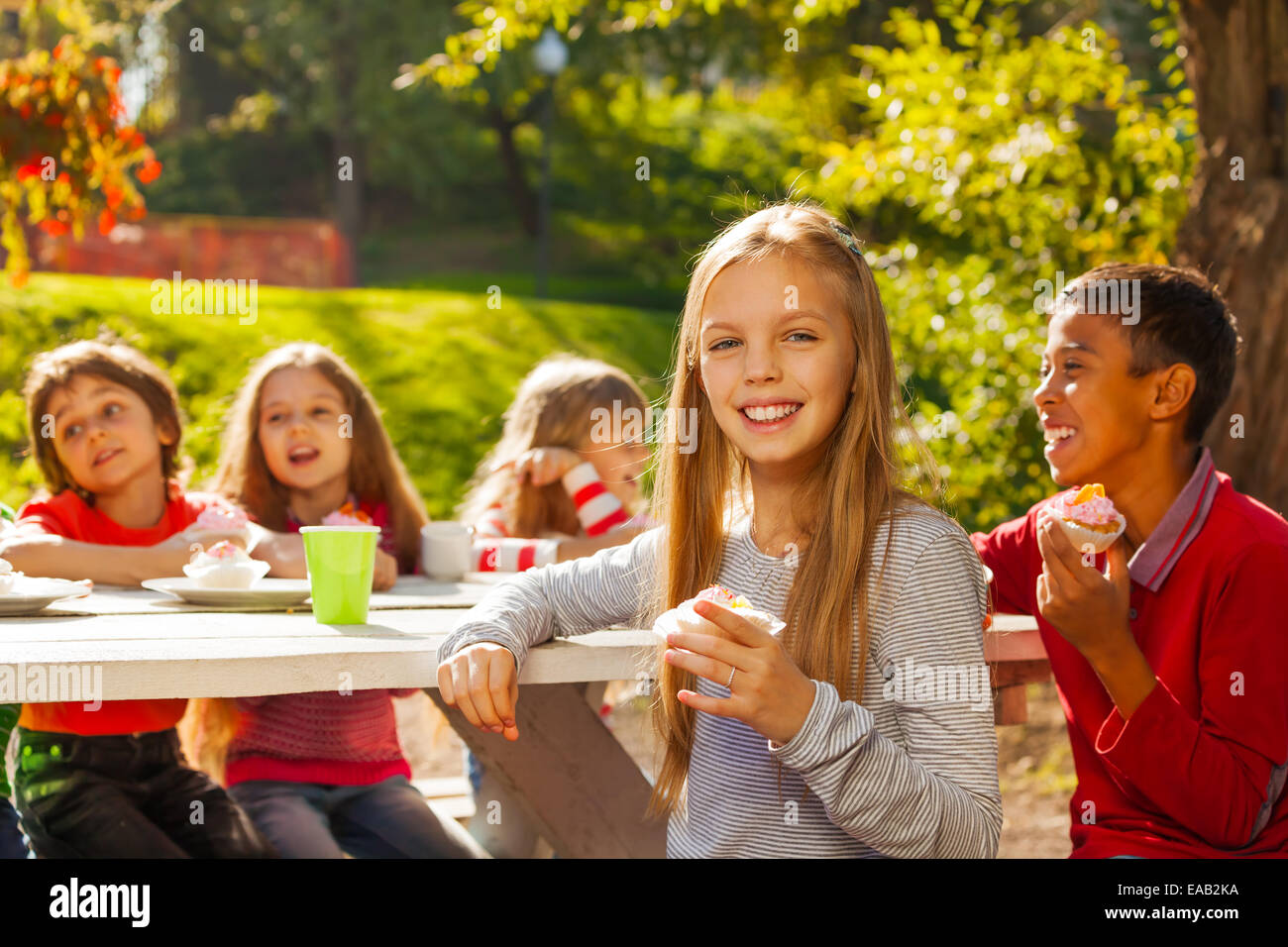 Happy group of children sitting at wooden table Stock Photo - Alamy