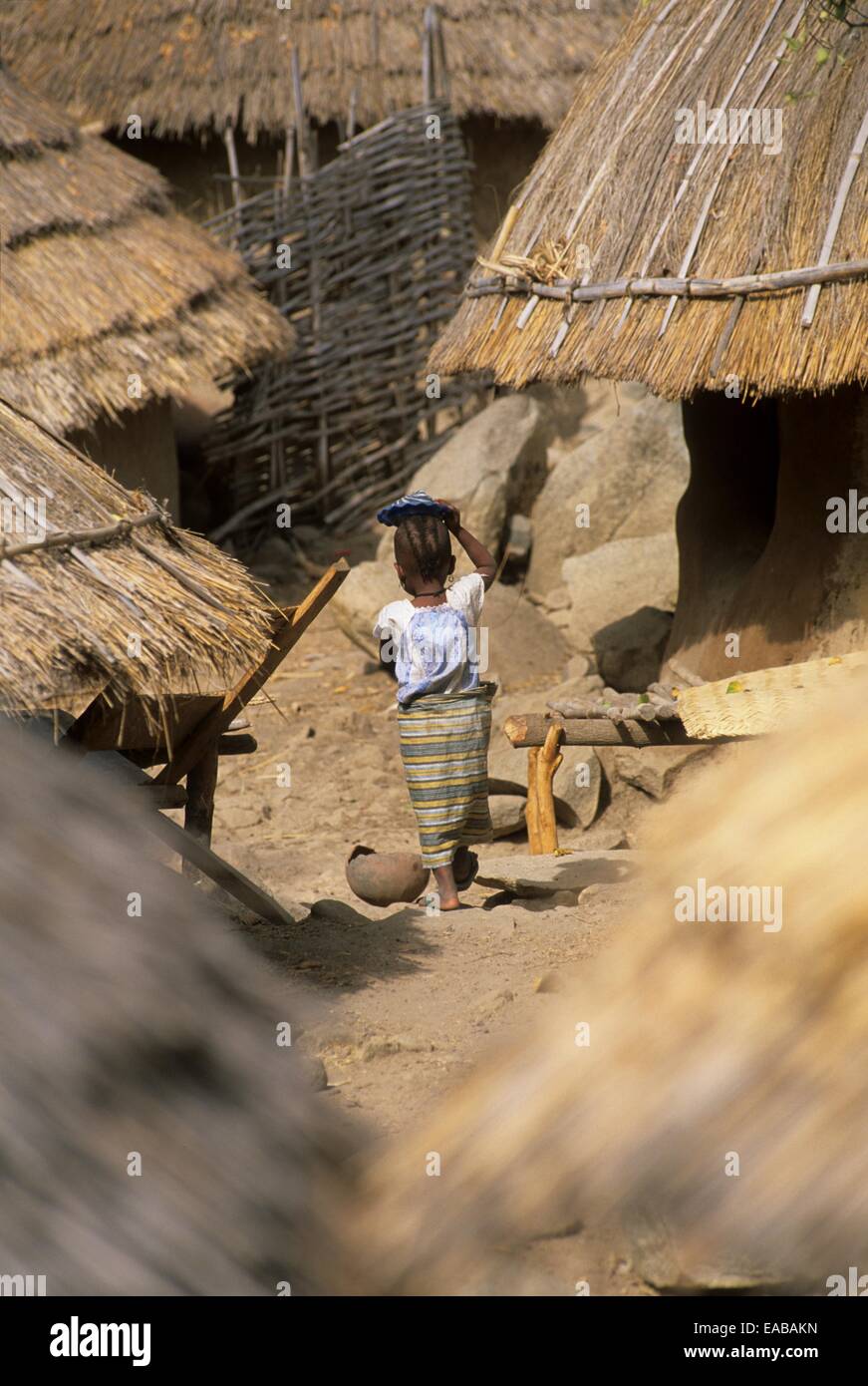 Young girl walking in typical Bedik Village, Bassari country, Senegal ...