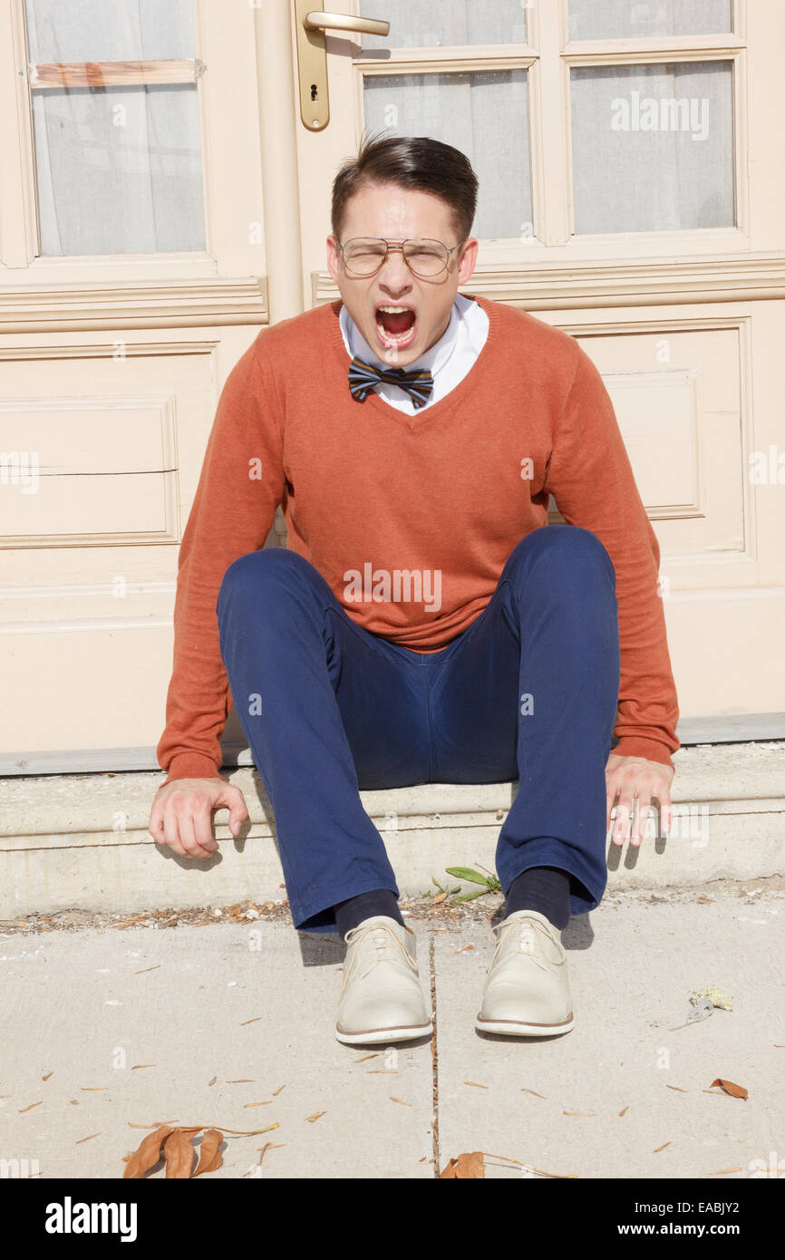 angry man with open mouth with glasses and sweater sitting on steps in ...