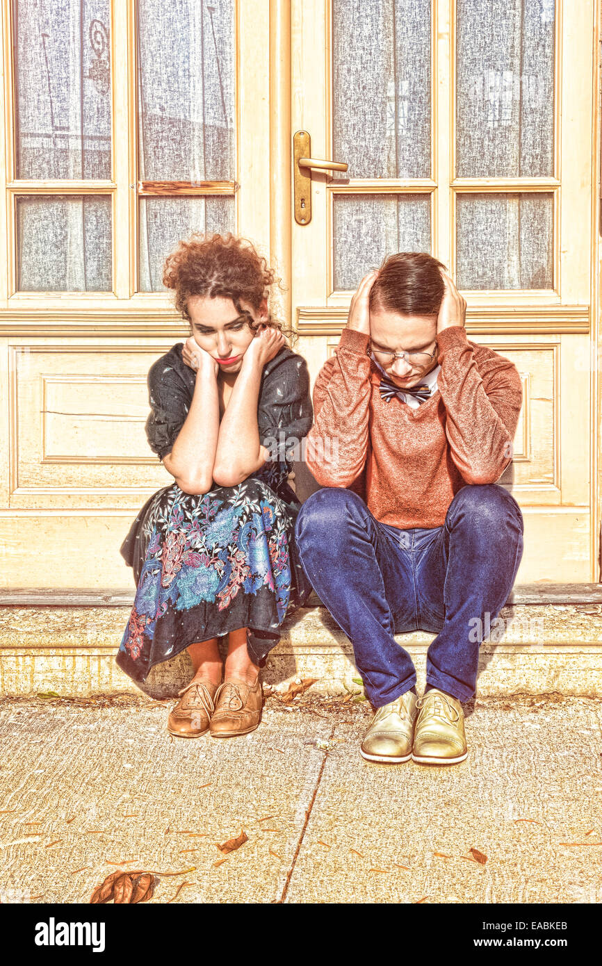 depressed and agitated man and woman crouching in front of the house at ...