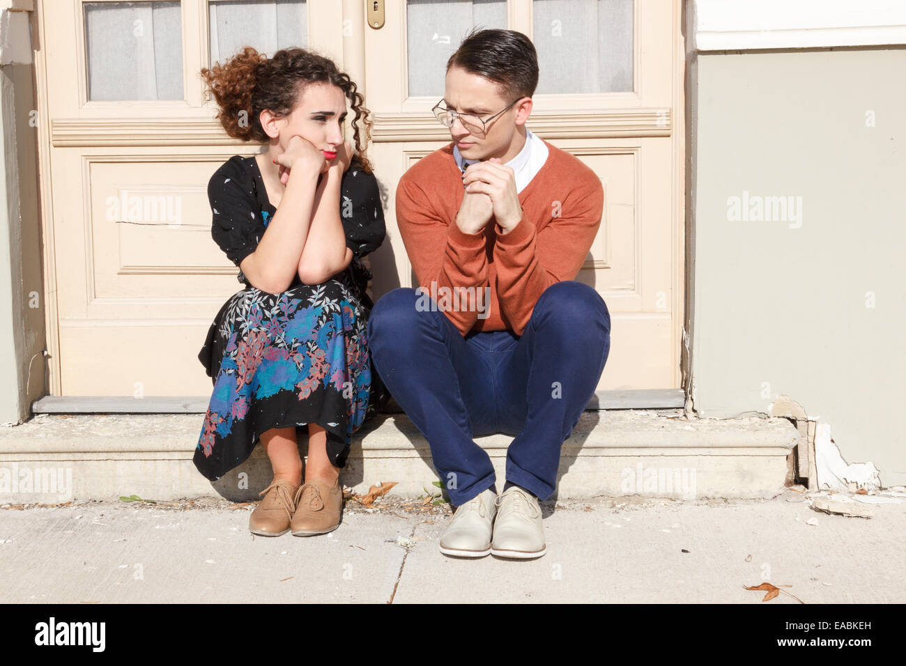 depressed and agitated man and woman crouching in front of the house at ...