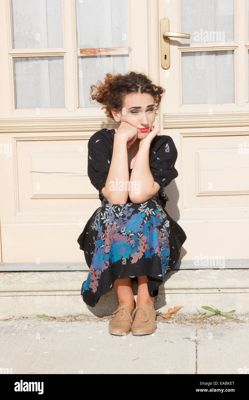 depressed and agitated woman crouching in front of the house at the ...