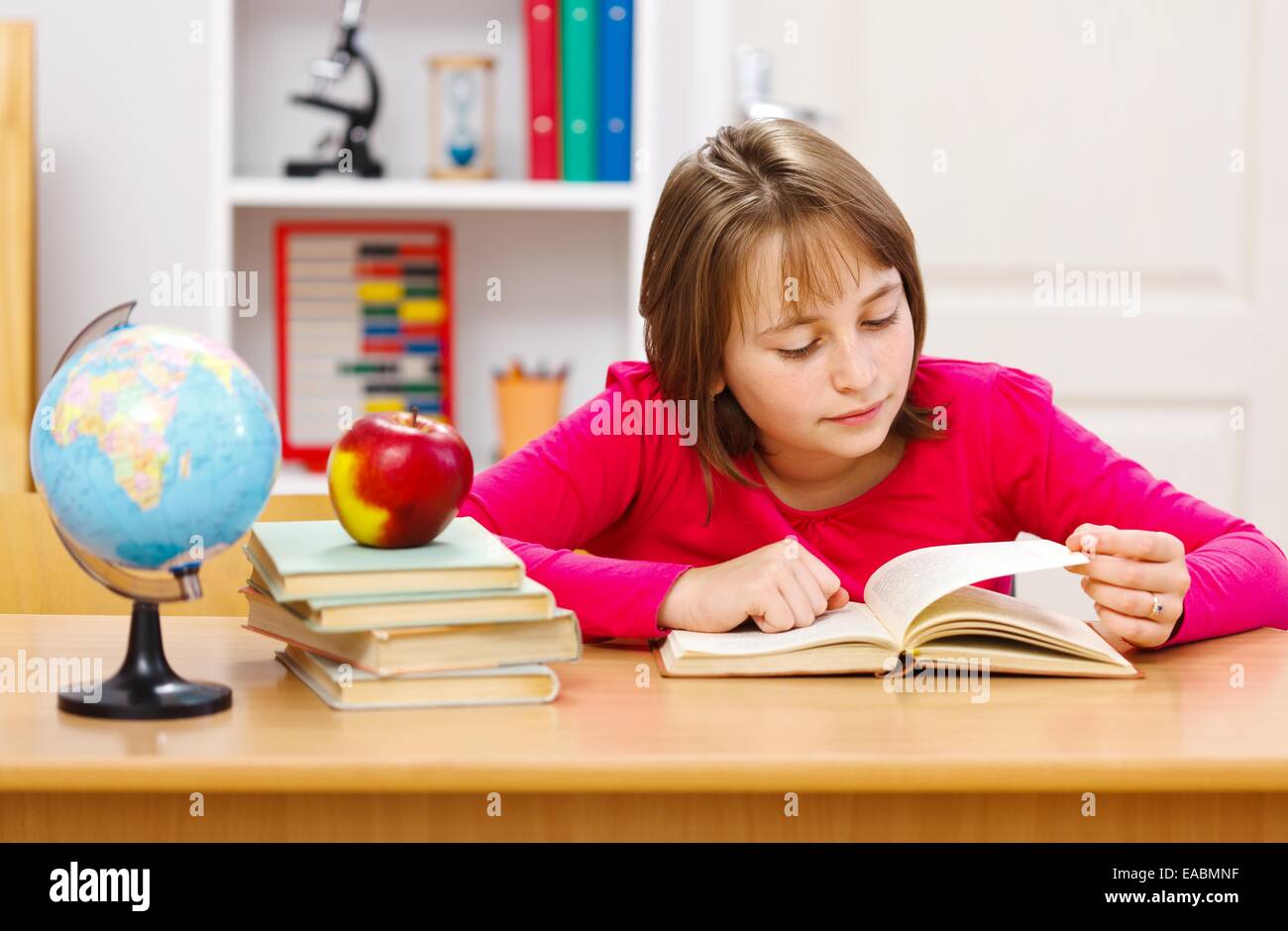 Teen girl reading book in classroom Stock Photo - Alamy