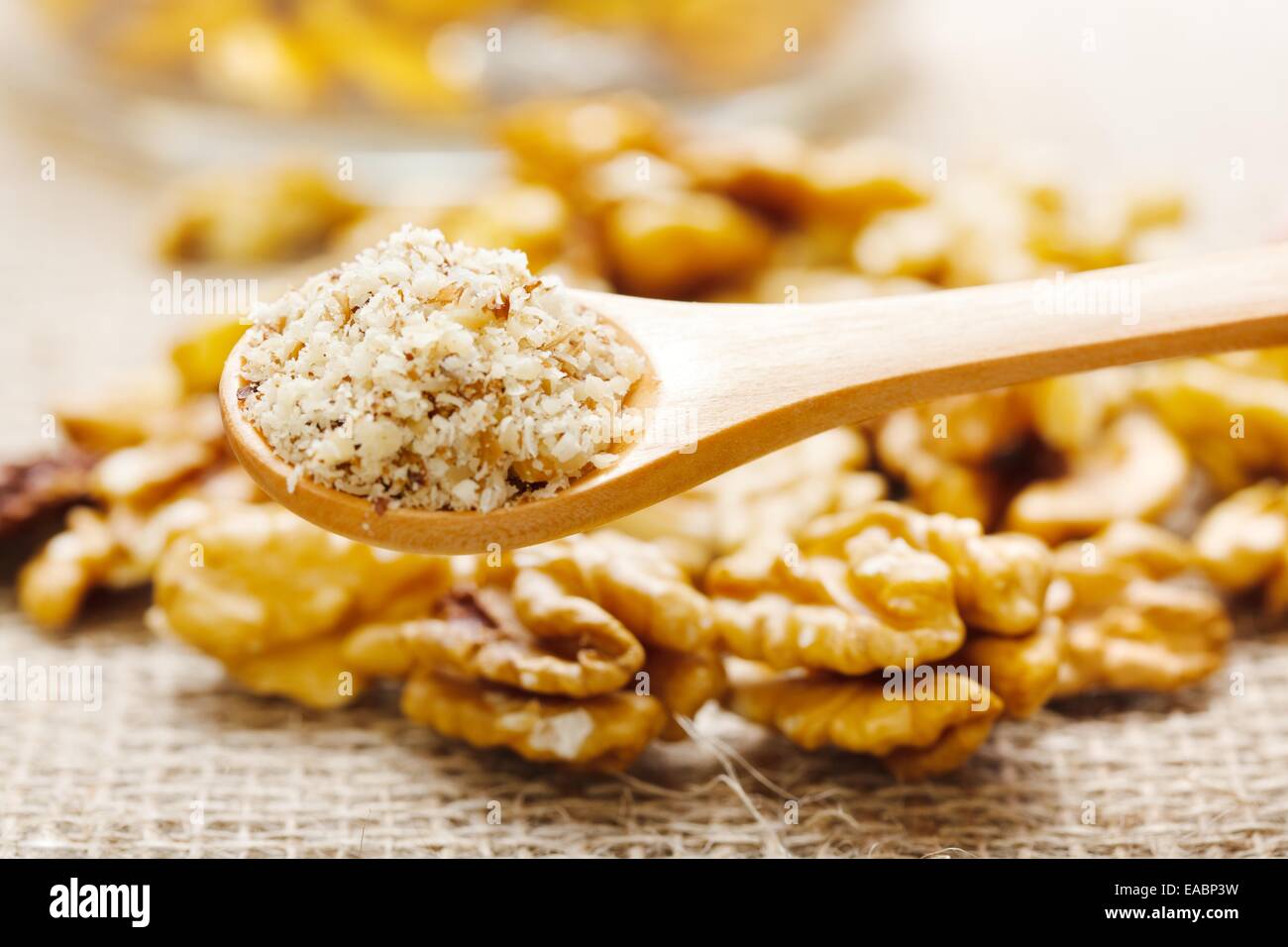 Walnut ground in wooden spoon, nutmeat in background Stock Photo - Alamy