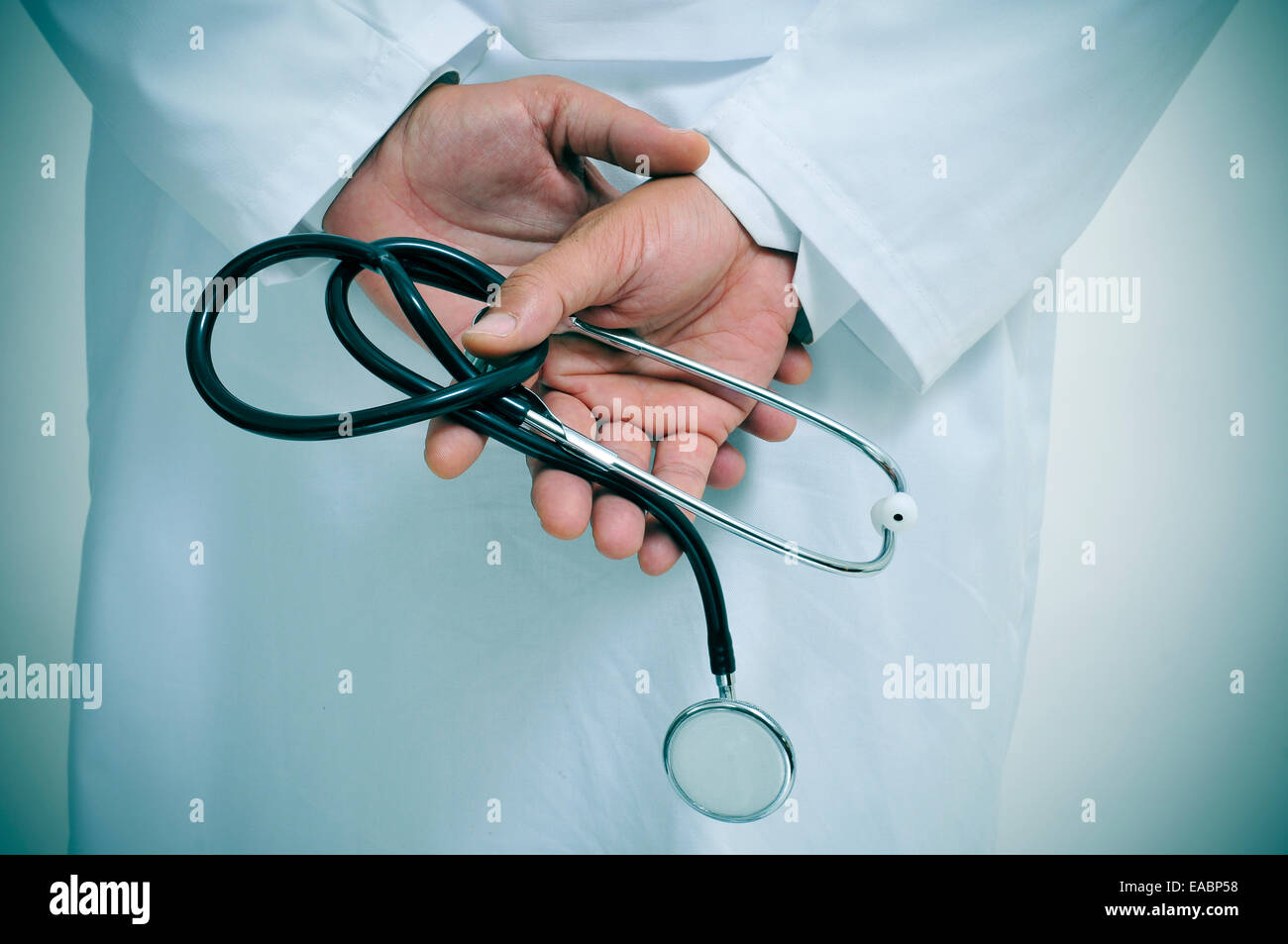 a doctor holding a stethoscope in his back Stock Photo - Alamy