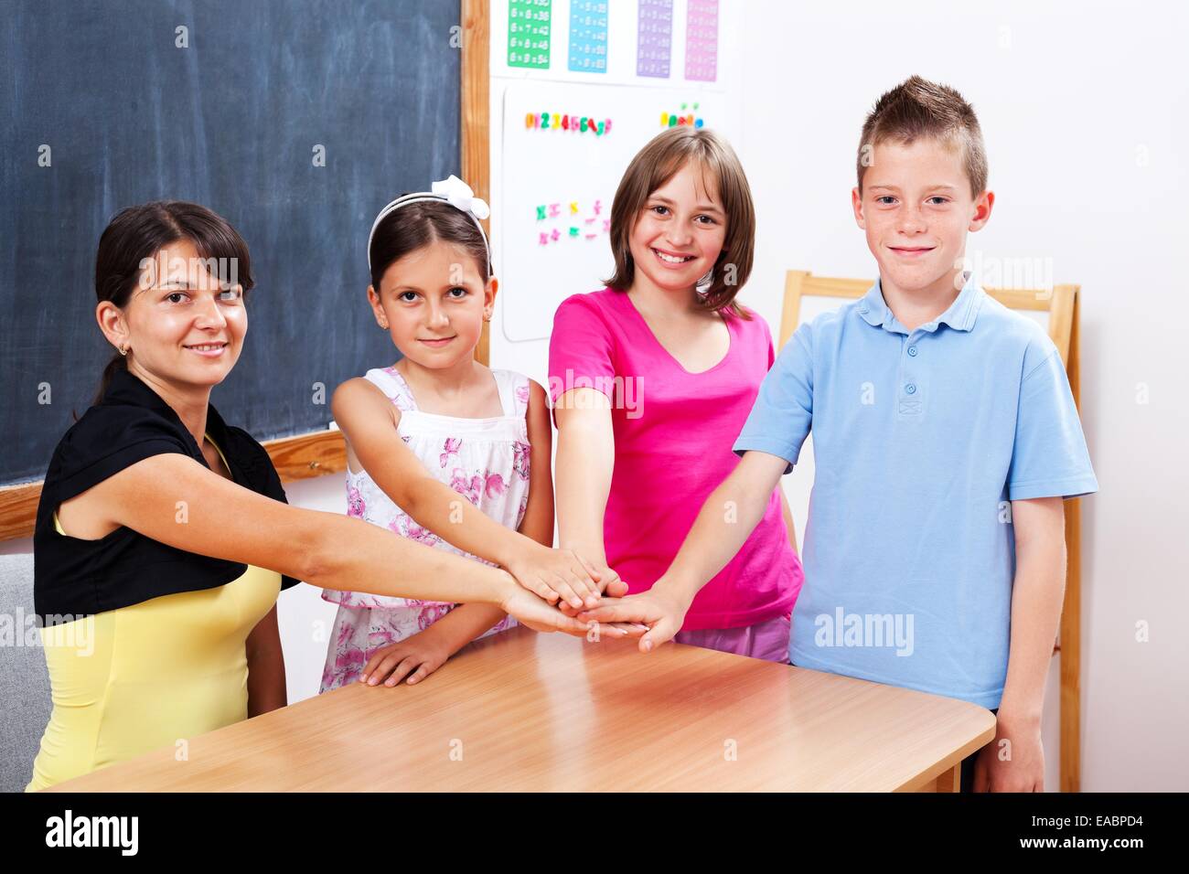 Group of united students and teacher, putting their hands together ...