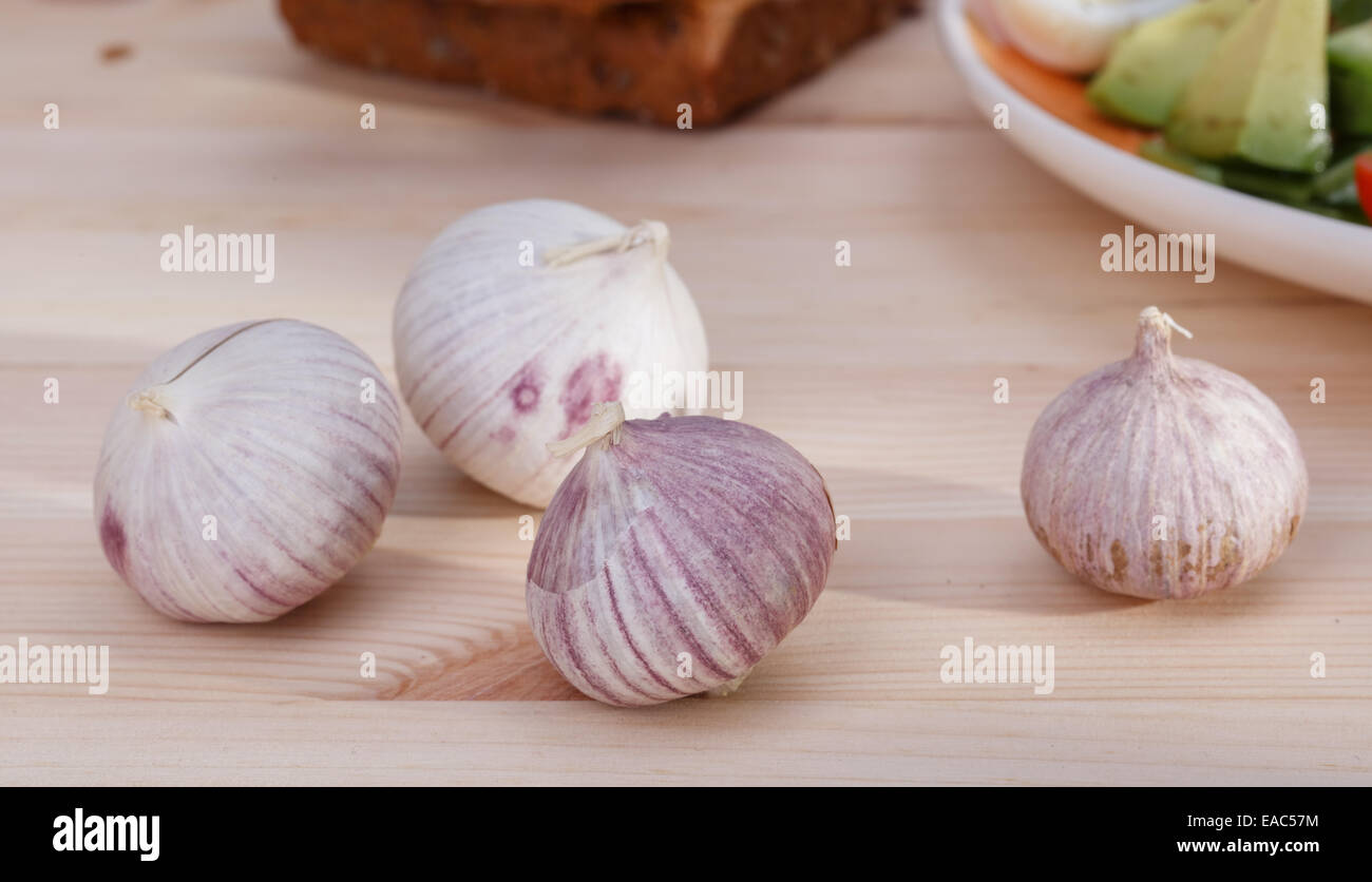 four small heads of garlic on a wooden table Stock Photo - Alamy