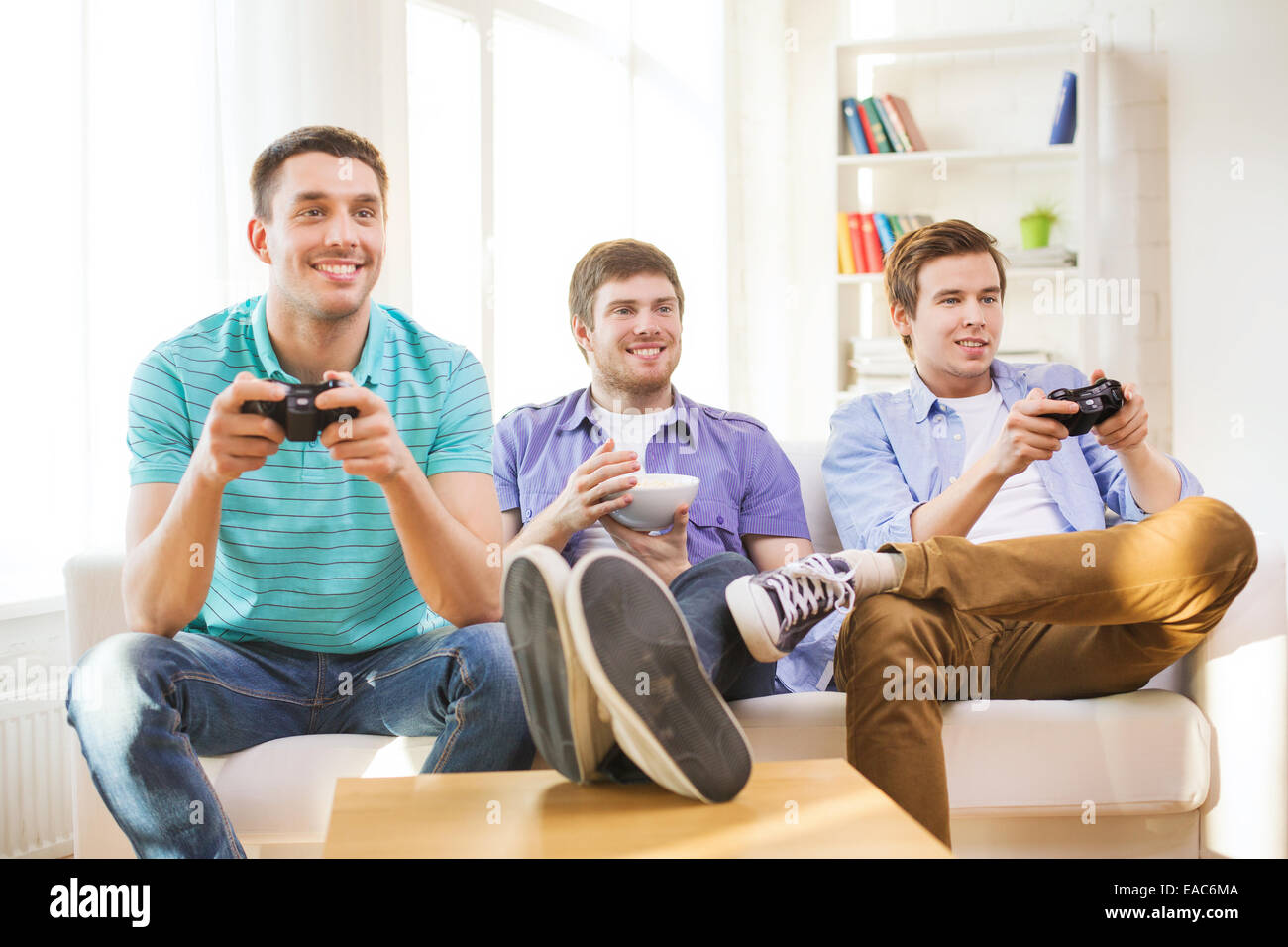 smiling friends playing video games at home Stock Photo - Alamy