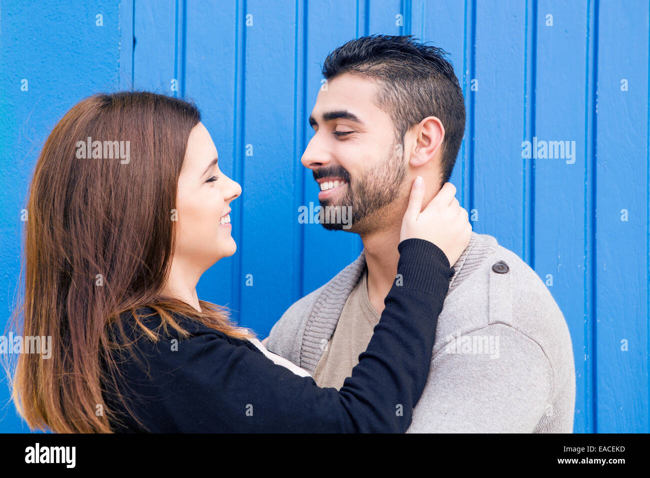 Young romantic couple hugging over blue background Stock Photo - Alamy