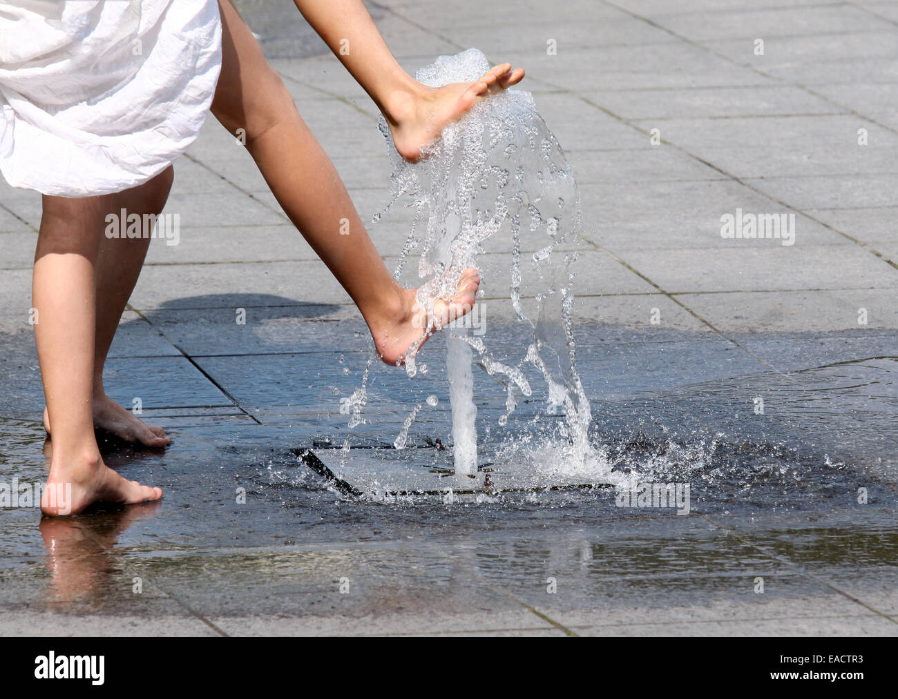Picture of the legs of two children playing with small fountain Stock ...