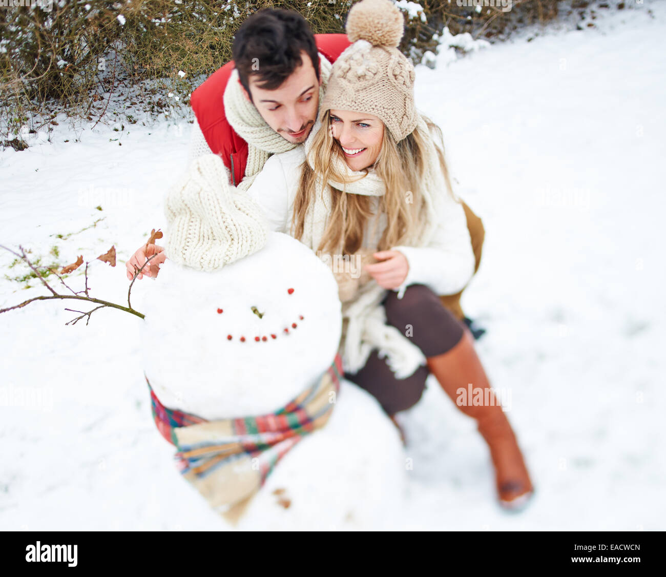 Happy couple in winter building a snowman together Stock Photo - Alamy