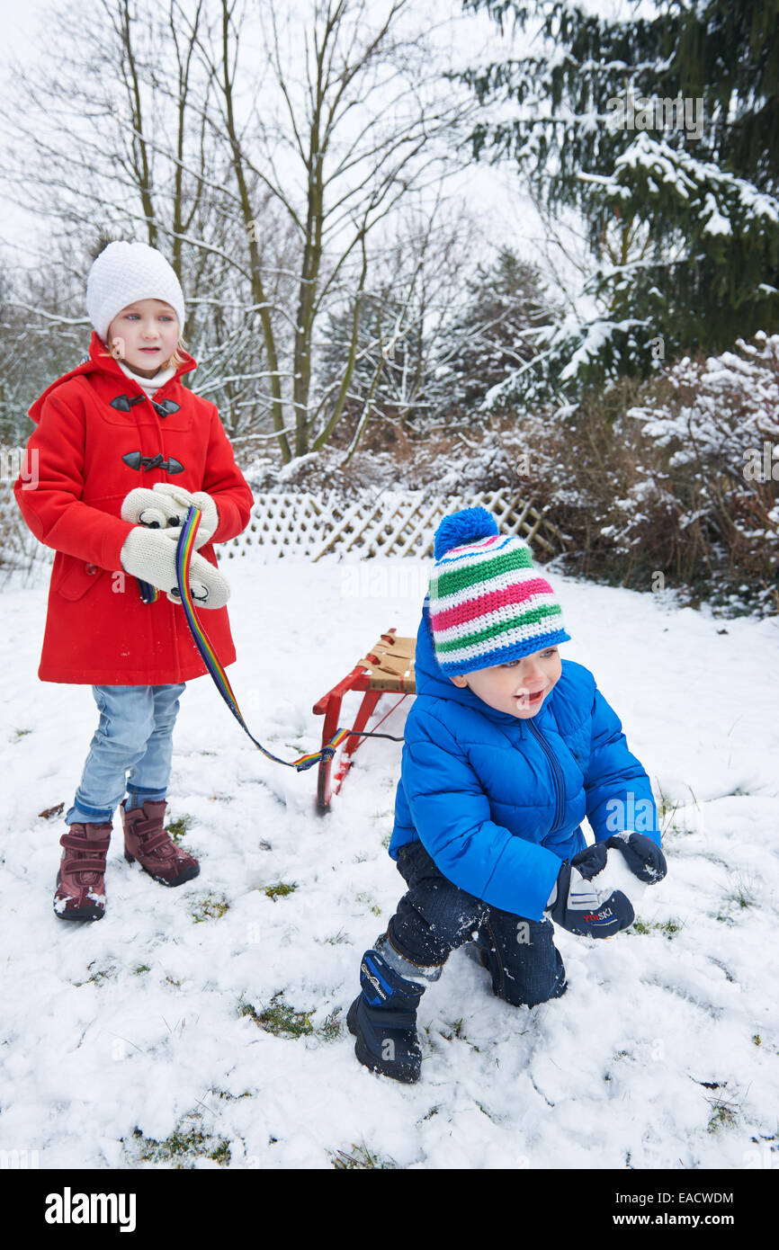 two children with a sled playing in snow in winter Stock Photo - Alamy