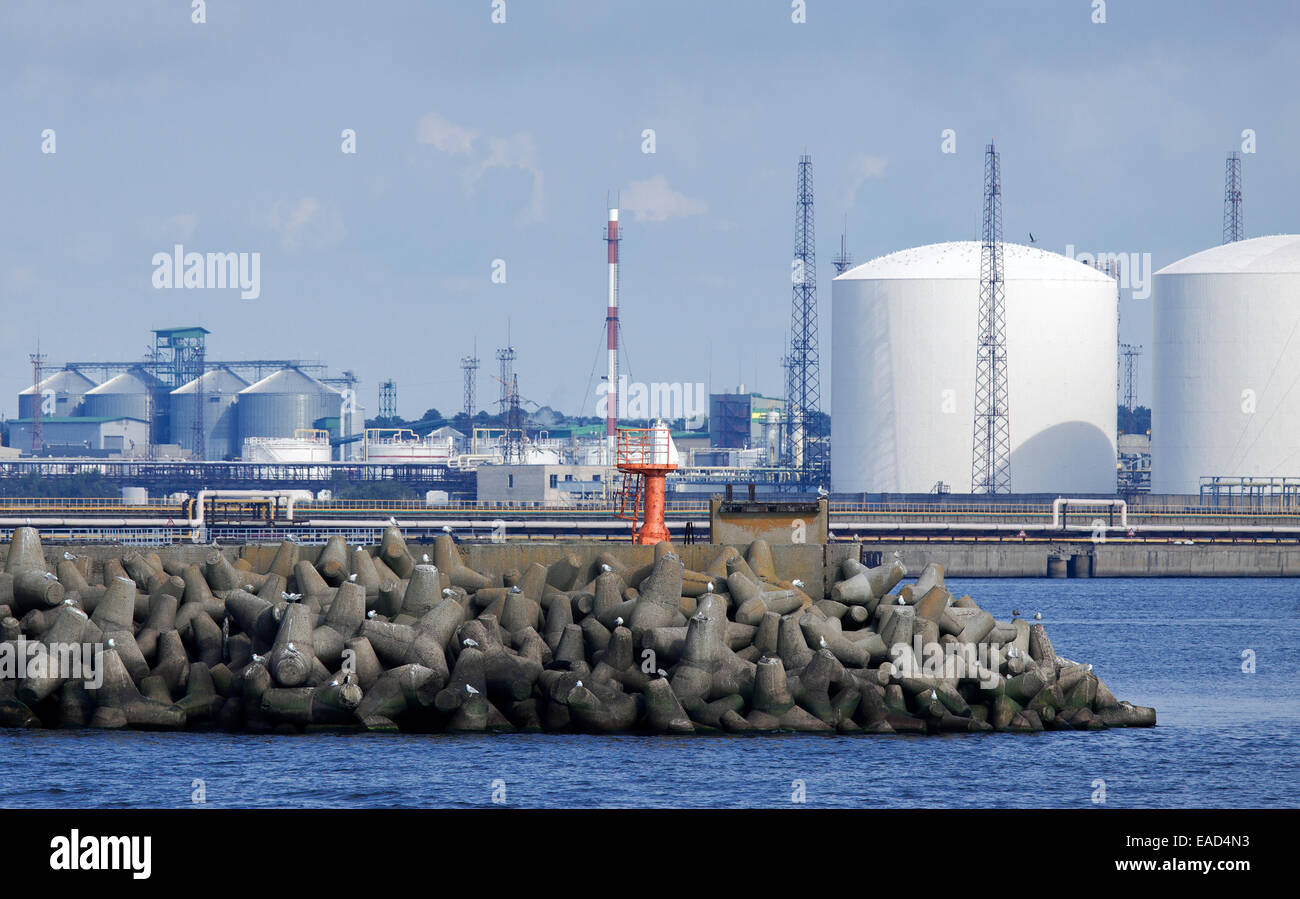 Sea port with storage tanks in background. Concrete pier in focus in ...