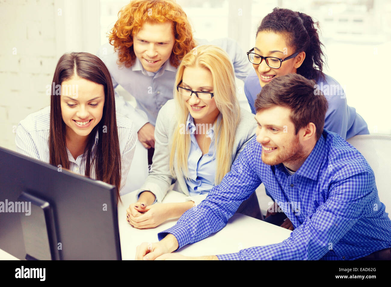 smiling business team looking at computer monitor Stock Photo - Alamy