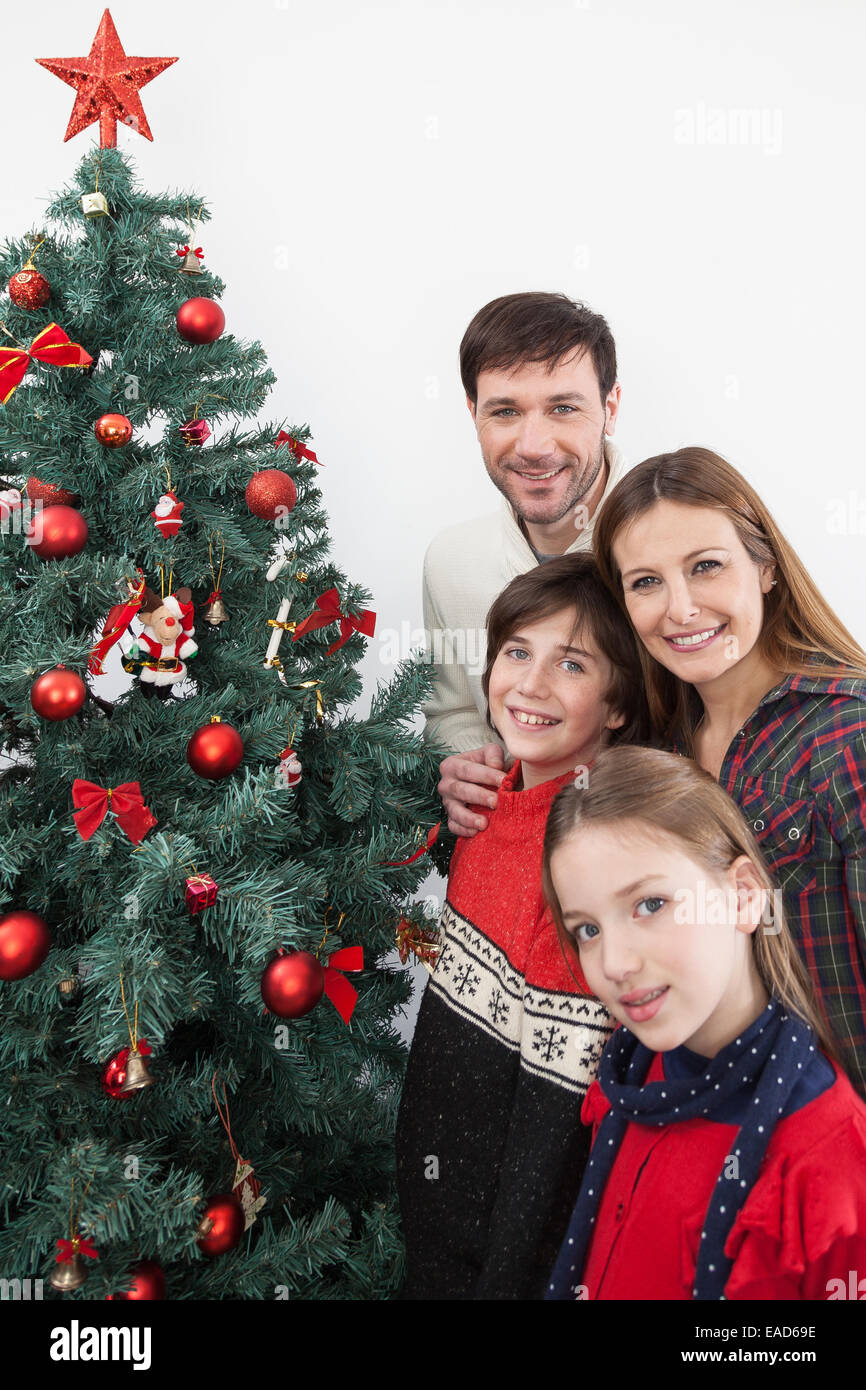 Happy family smiling beside the Christmas tree Stock Photo - Alamy