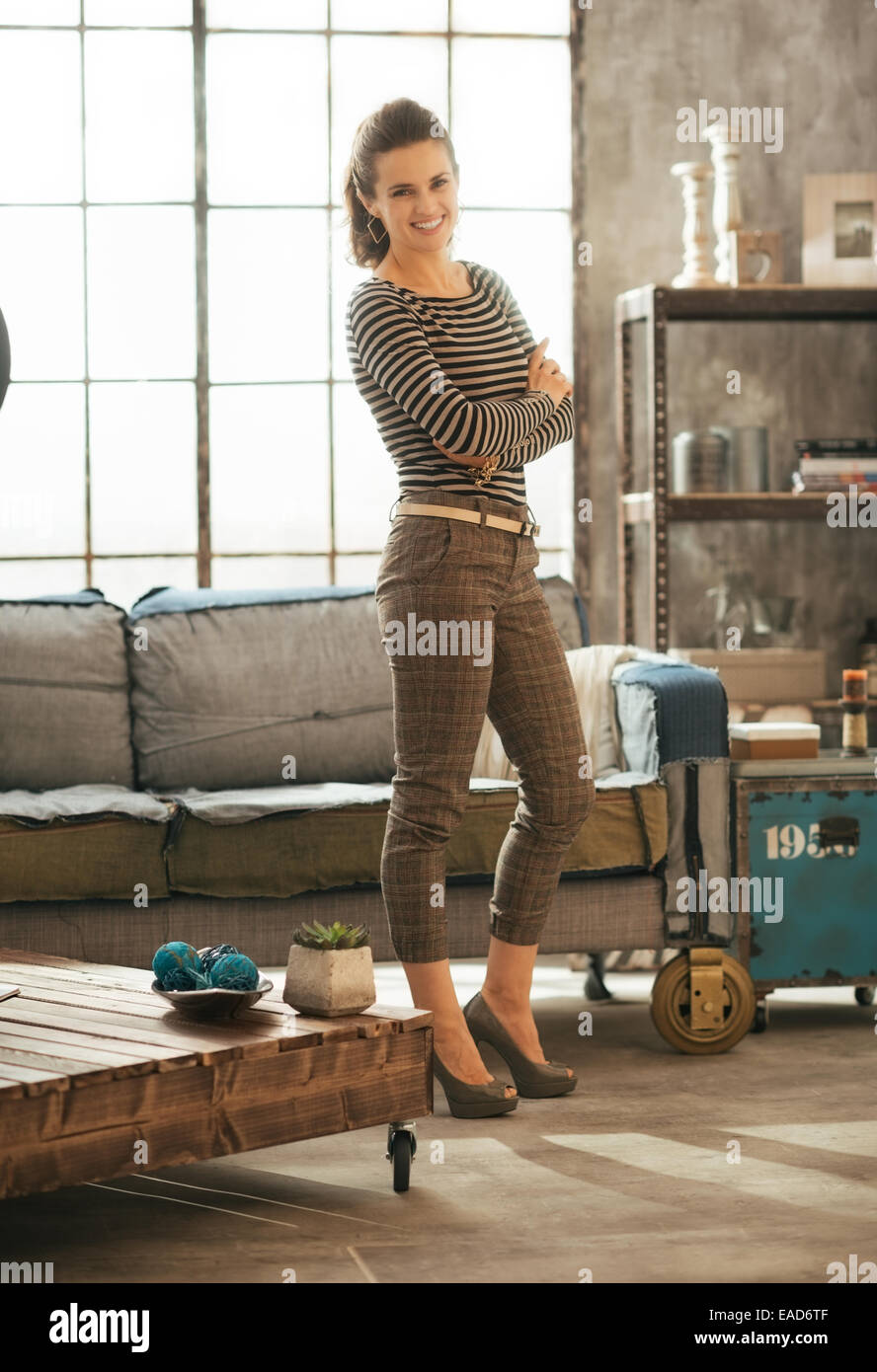 Full length portrait of happy young woman standing in loft apartment ...