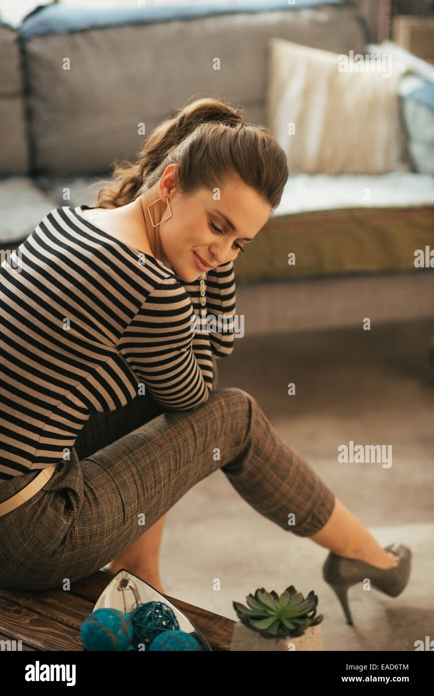 Young woman sitting in loft apartment Stock Photo - Alamy