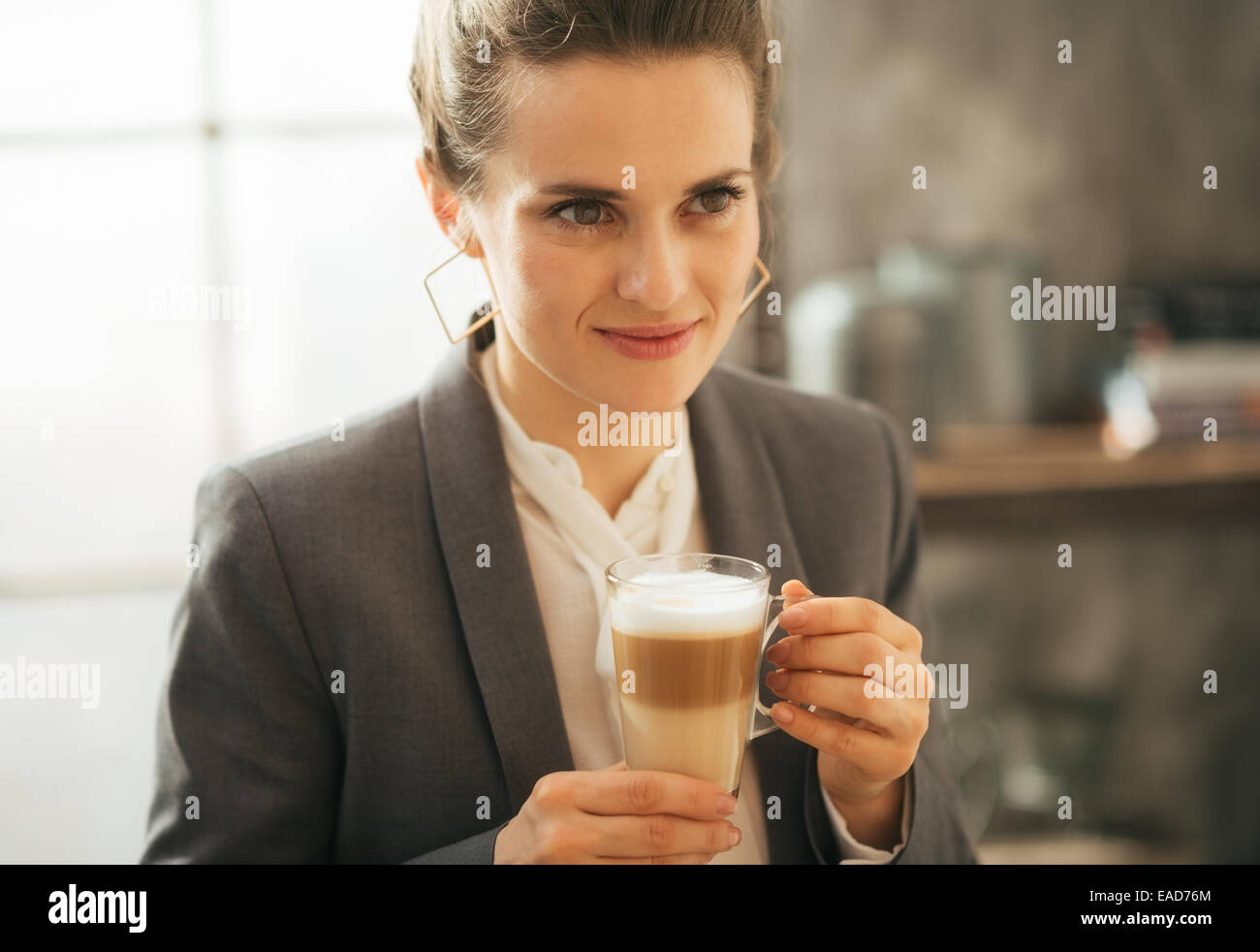Portrait of happy business woman drinking coffee latte in loft ...