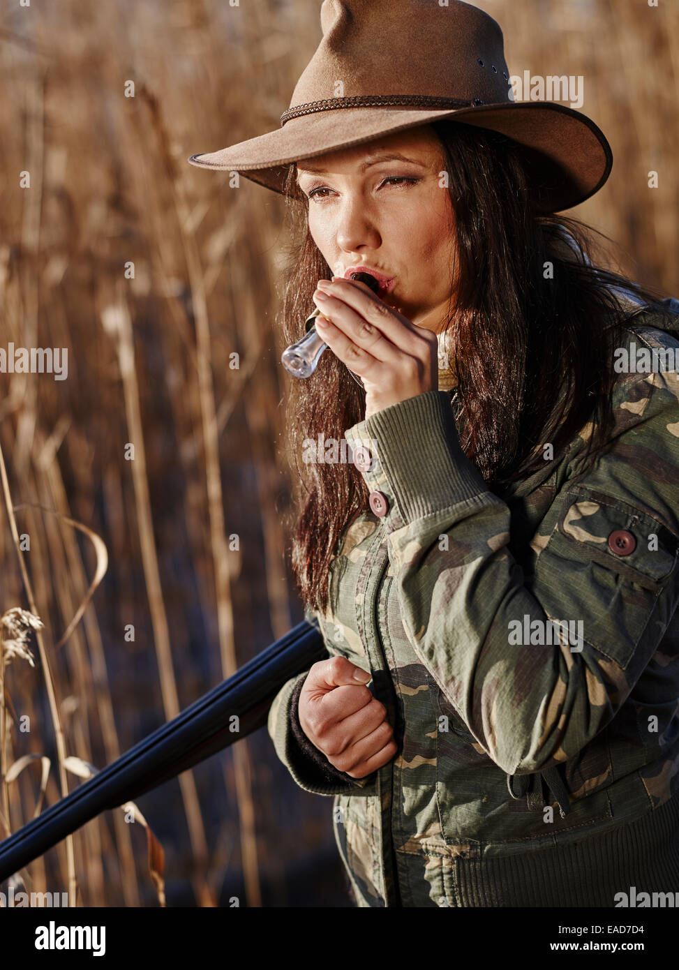 Waterfowl hunting, the female hunter carry a shotgun and she use a duck ...