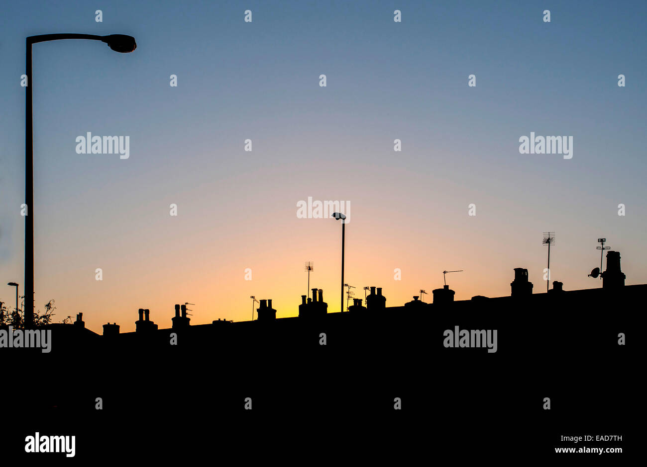 Sunset going down behind urban rooftops in silhouette Stock Photo - Alamy