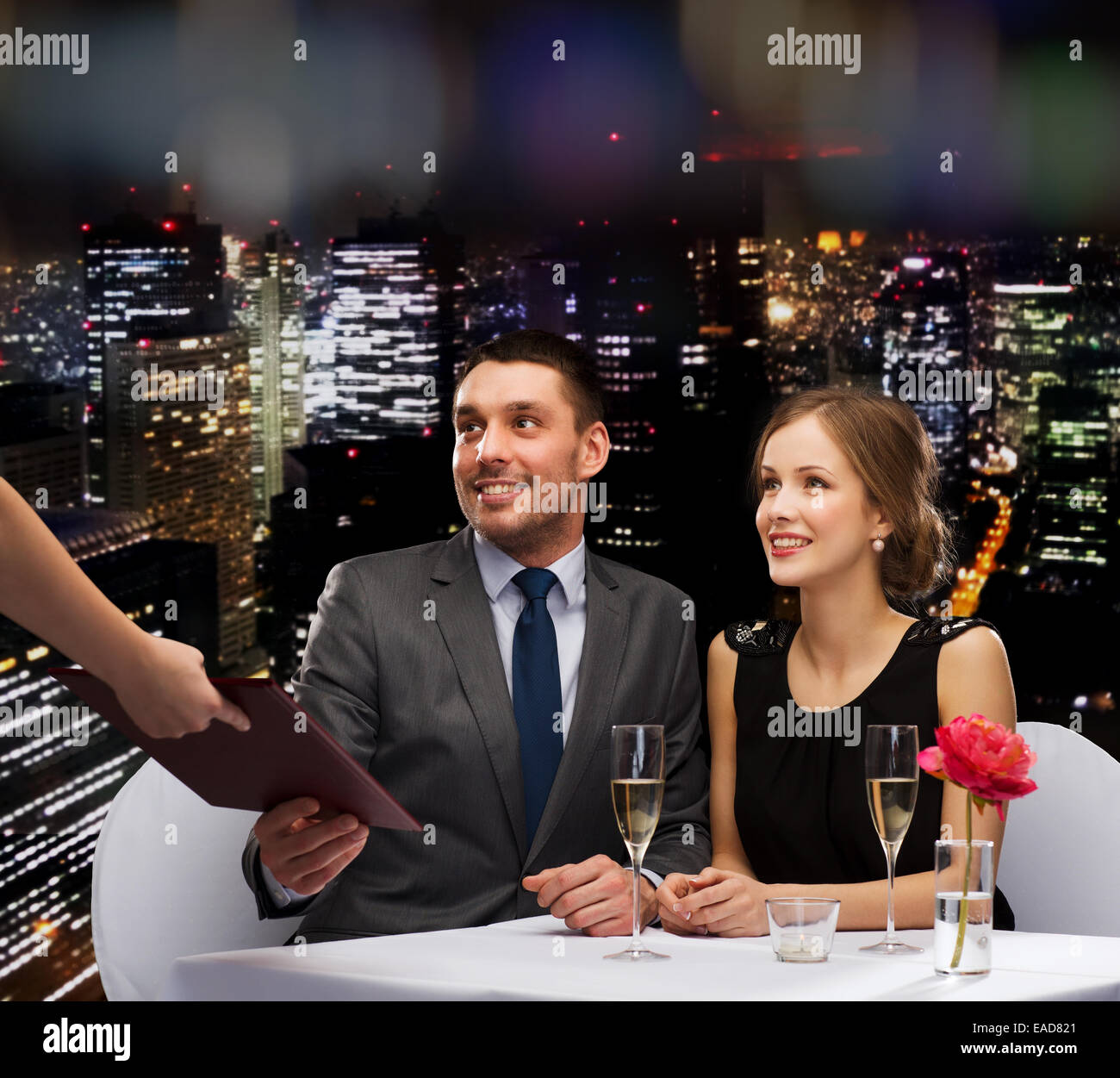 waiter giving menu to happy couple at restaurant Stock Photo - Alamy