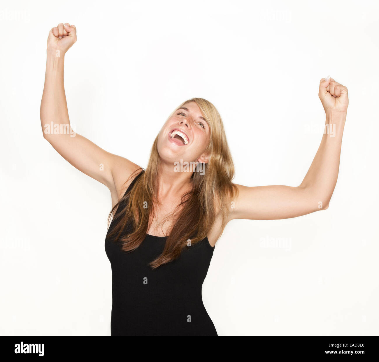 A young woman exults and rejoices. She stretches her arms in the air ...