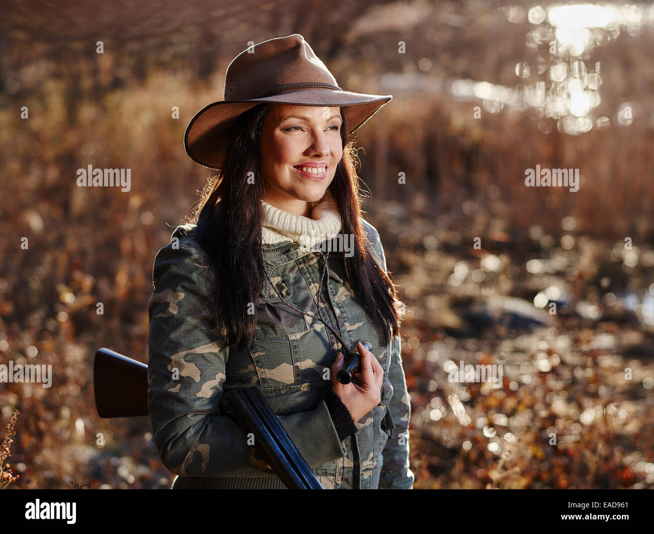 Waterfowl hunting, the female hunter carry a shotgun, autumnal bushes ...