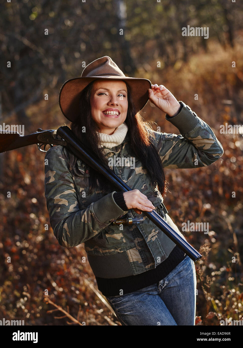 Waterfowl hunting, the female hunter carry a shotgun, autumnal bushes ...