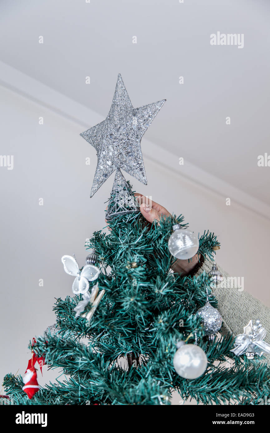 Man putting the star of christmas tree Stock Photo - Alamy