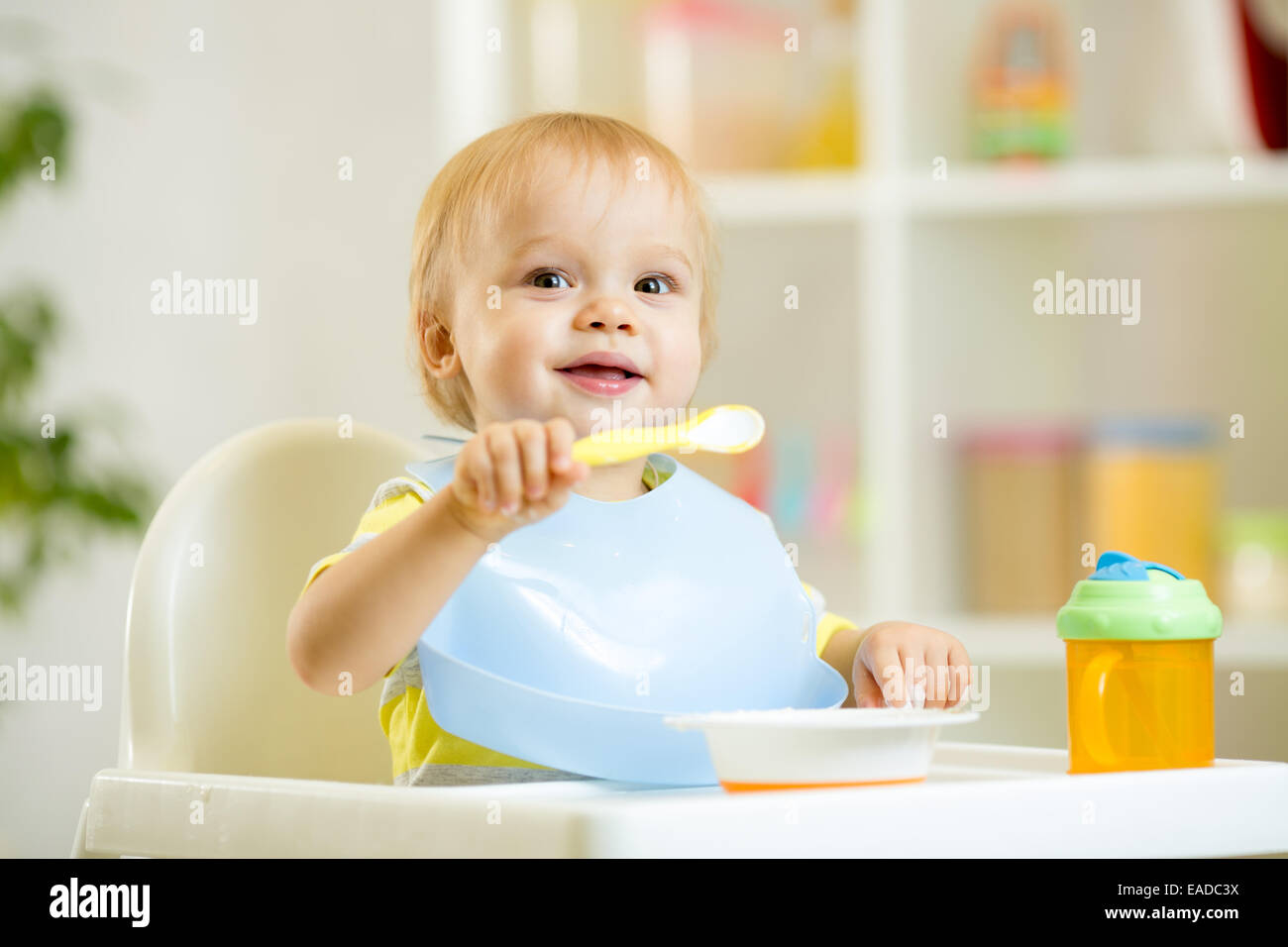funny baby child boy eating itself with spoon in kitchen Stock Photo ...