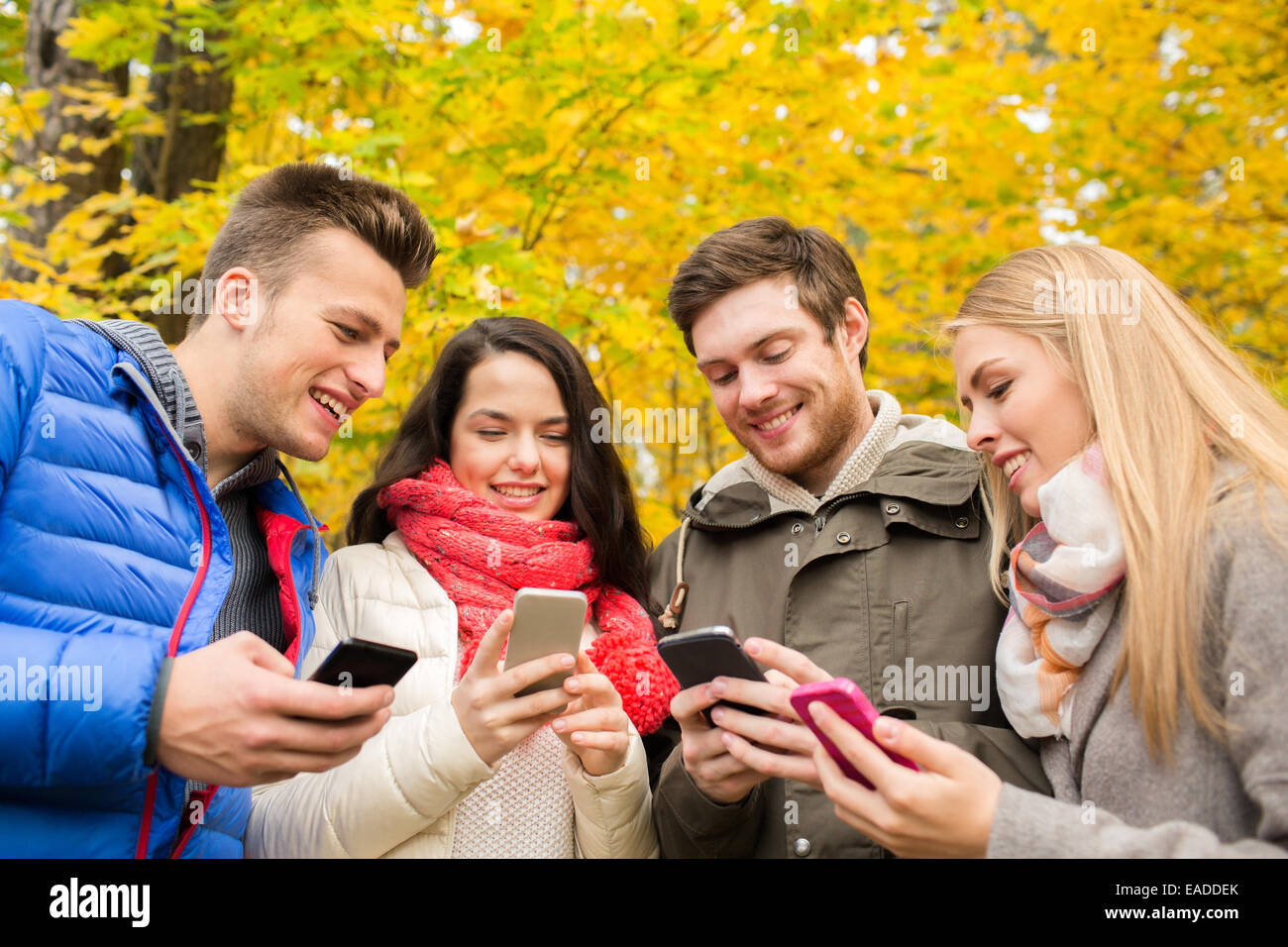 smiling friends with smartphones in city park Stock Photo - Alamy