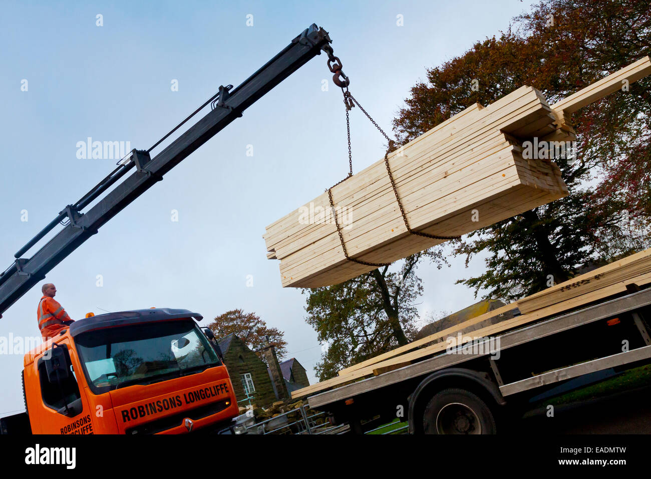 Extendable crane being used to lift wooden planks from the back of a ...