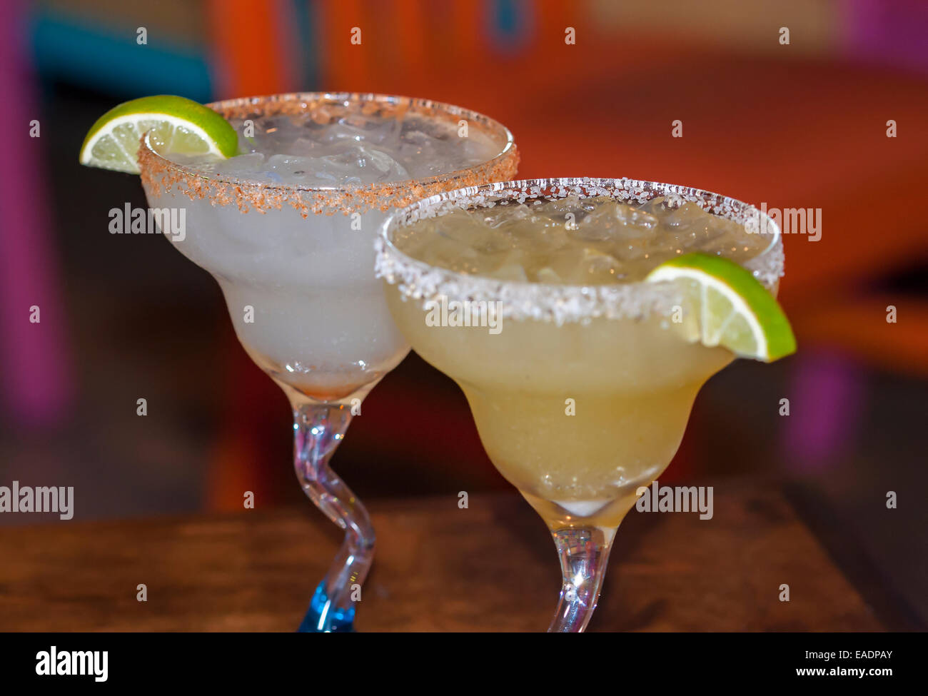 Two margaritas in salt rimmed fancy cocktail glasses, one ghost chilli ...
