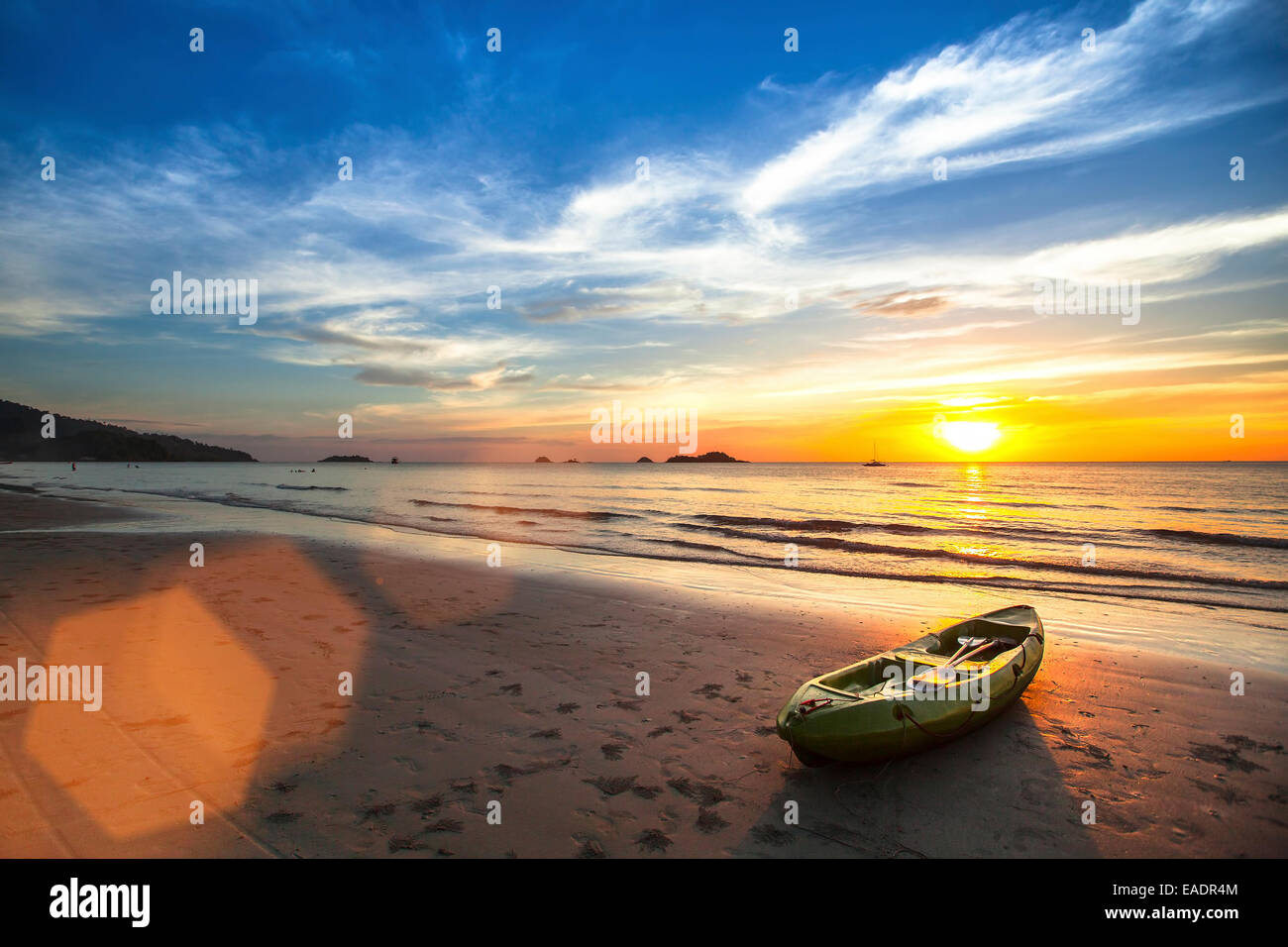 Tropical landscape. Canoe on the ocean beach during the amazing sunset ...