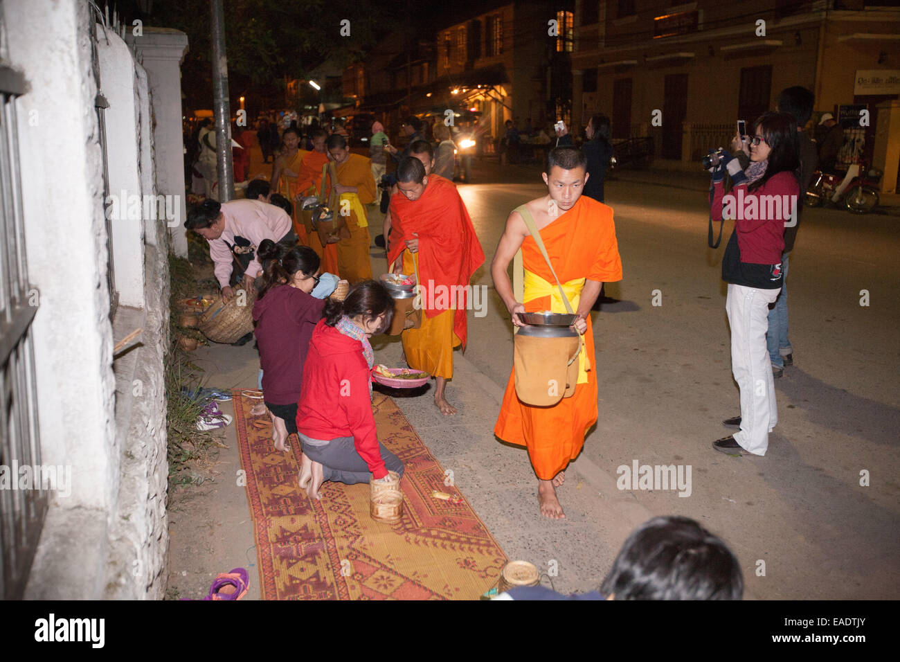 Buddhist monks on a very early alms walk with begging bowls to receive ...