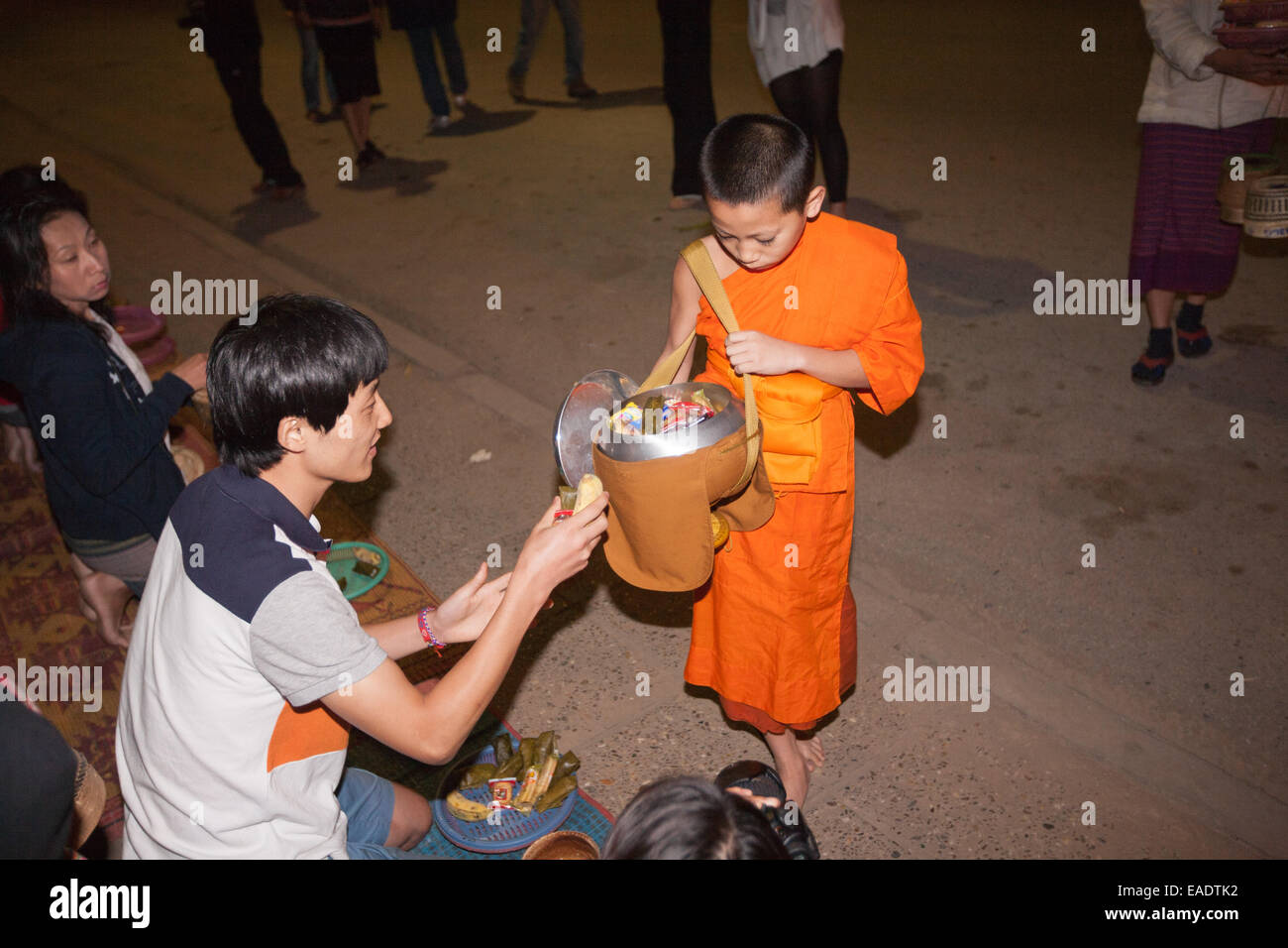 Buddhist monks on a very early alms walk with begging bowls to receive ...
