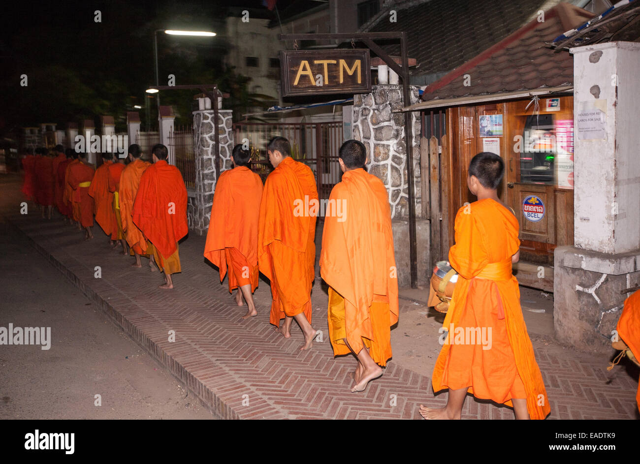 Buddhist monks on a very early alms walk with begging bowls to receive ...