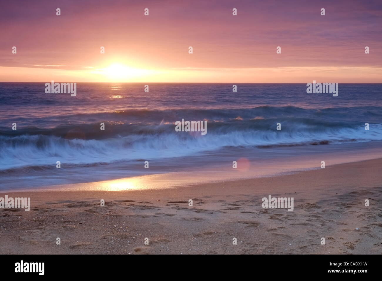 Beach waves crashing onto the shore during sunset Stock Photo - Alamy