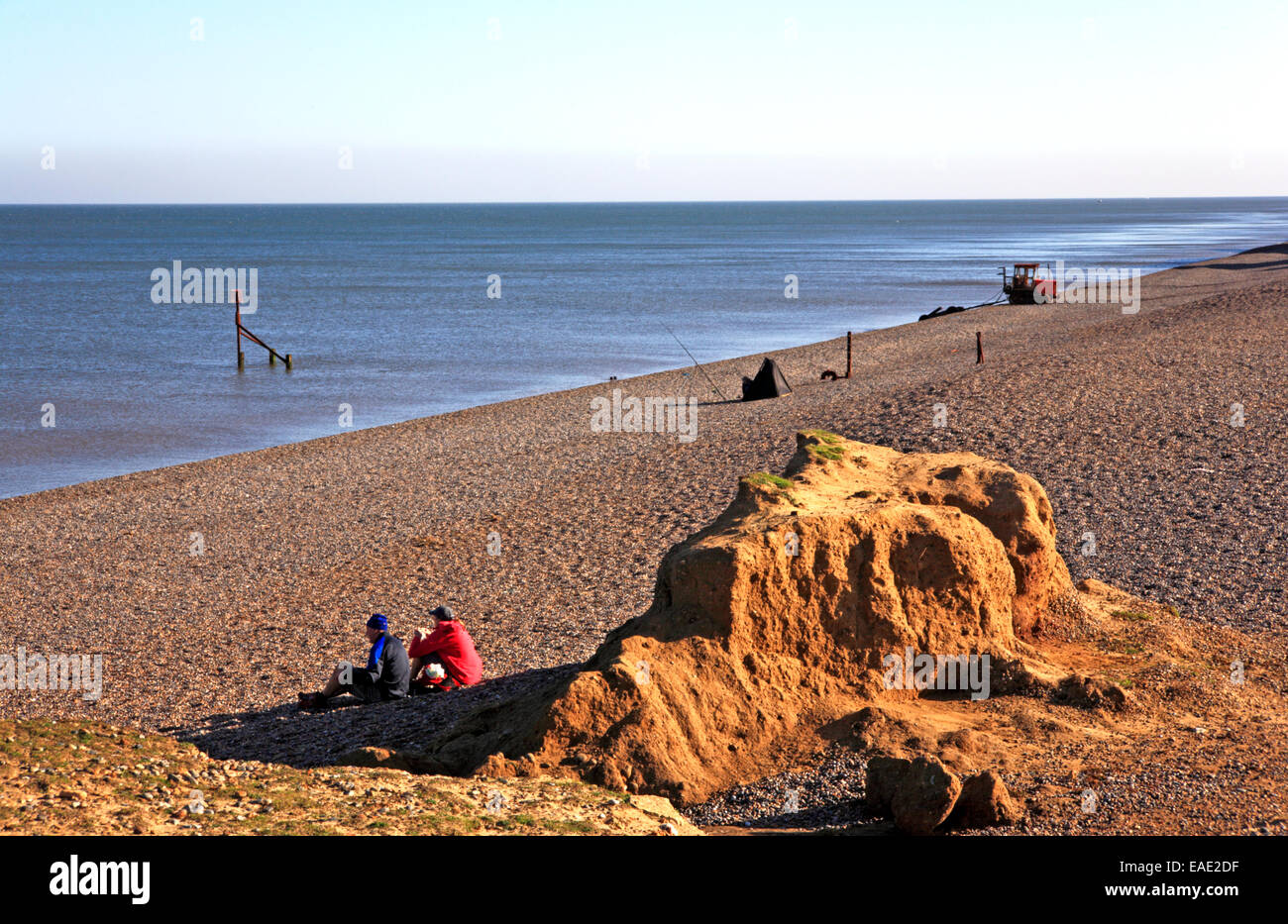 A couple having a picnic in the shelter of a low cliff on a fine autumn ...