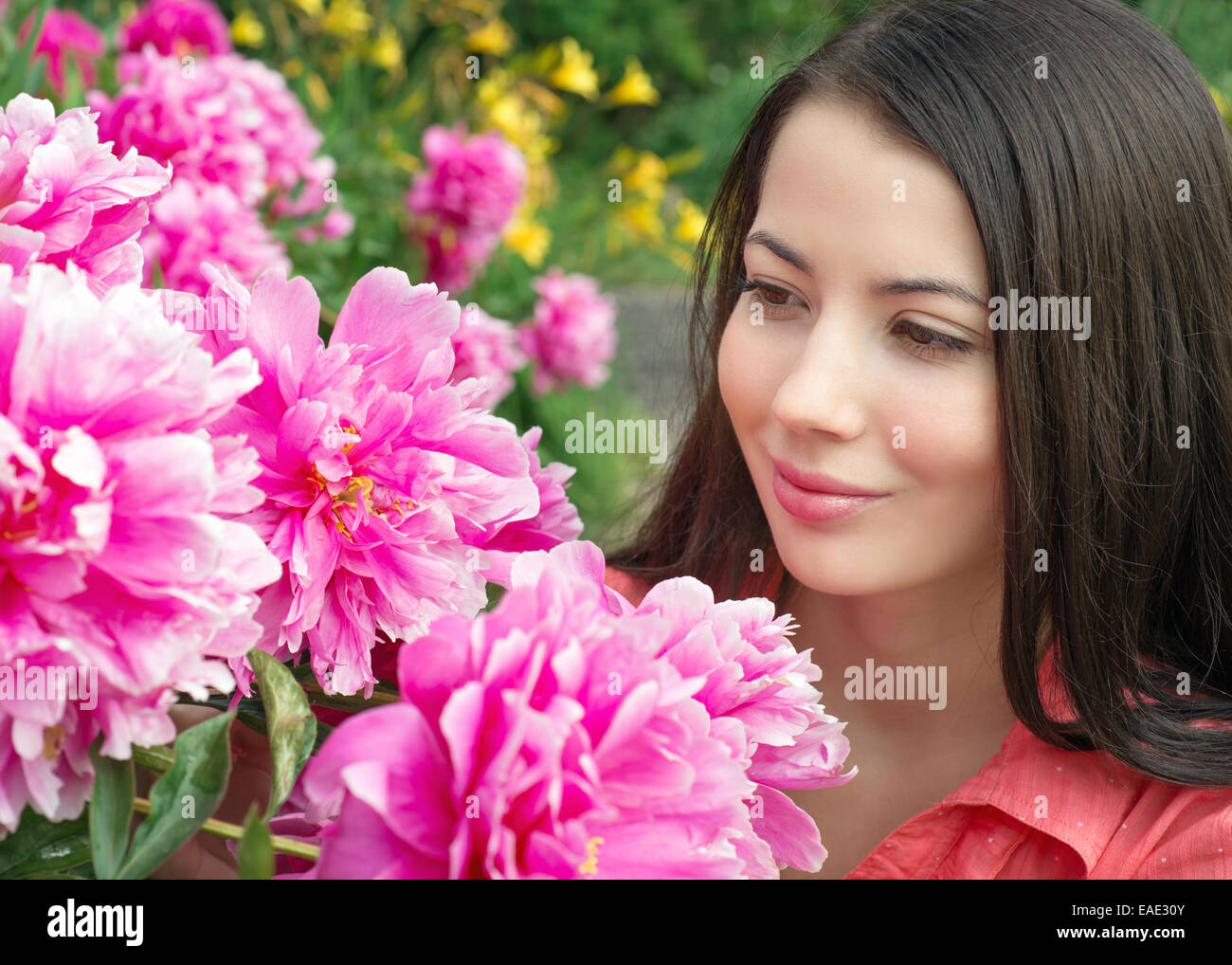 Young woman looking at flowers peonies Stock Photo - Alamy