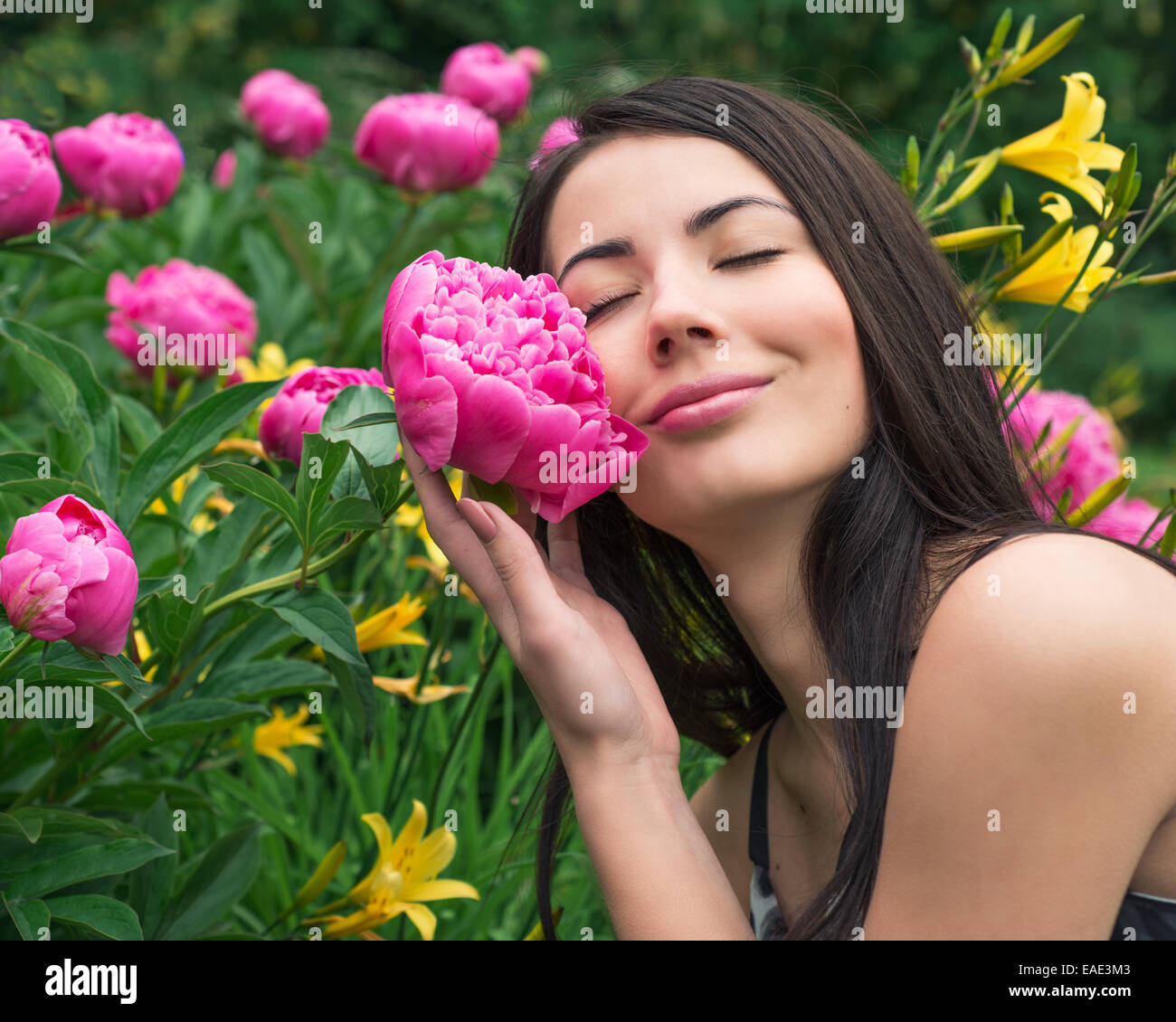 Young woman smelling a flower peony Stock Photo - Alamy