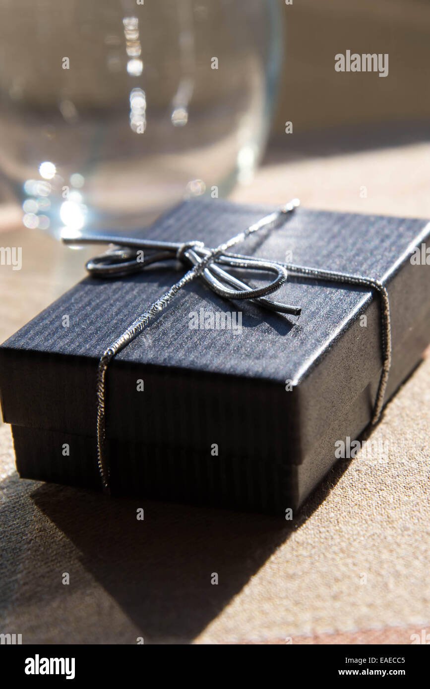 small black jewelry gift box with a silver bow in morning sunlight ...