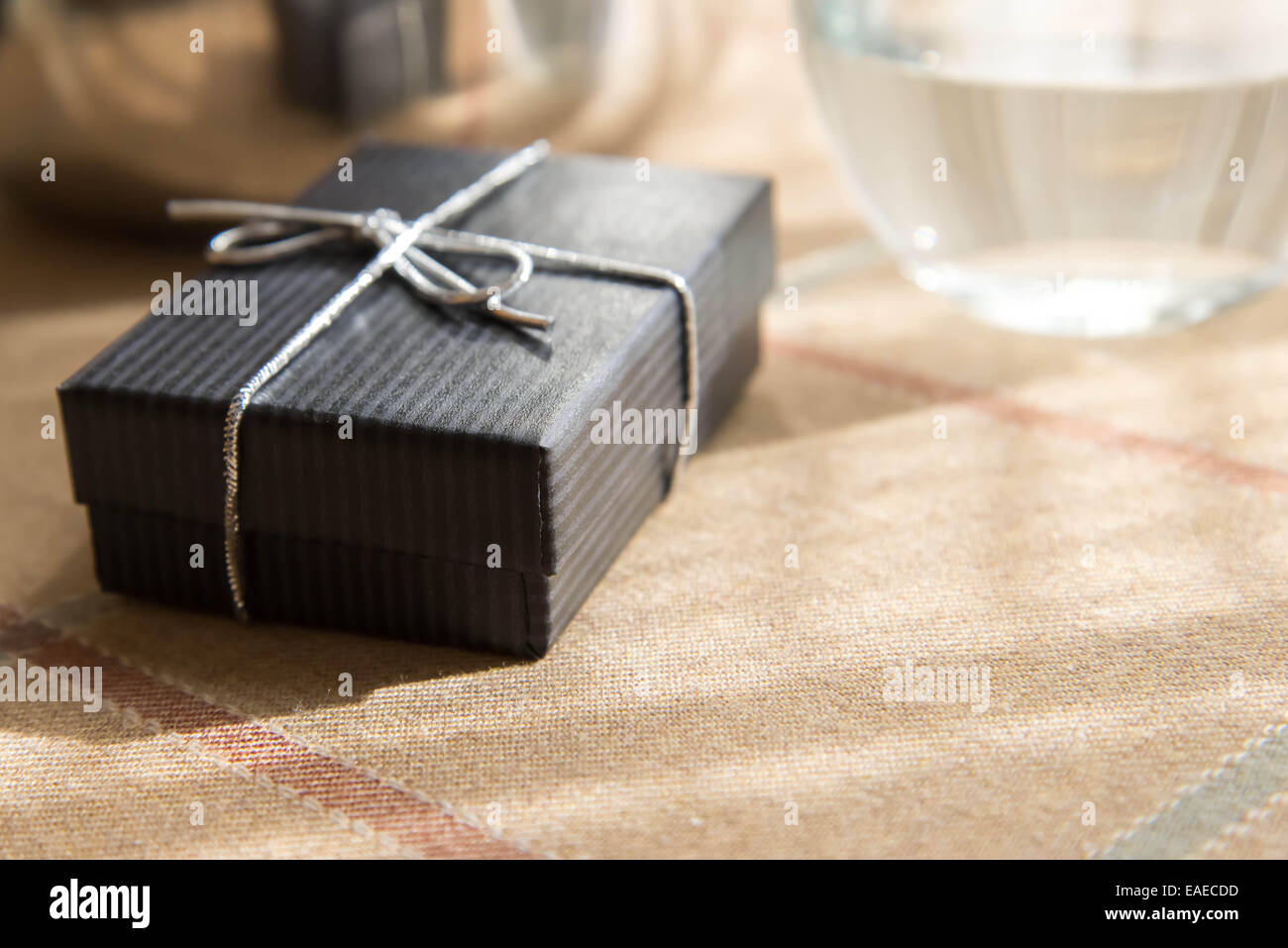 small black jewelry gift box with a silver bow in morning sunlight ...