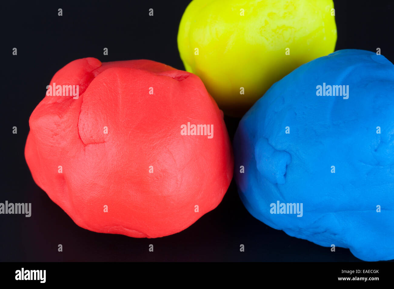 Colorful child's play clay (Red, Yellow, Blue) on black background ...