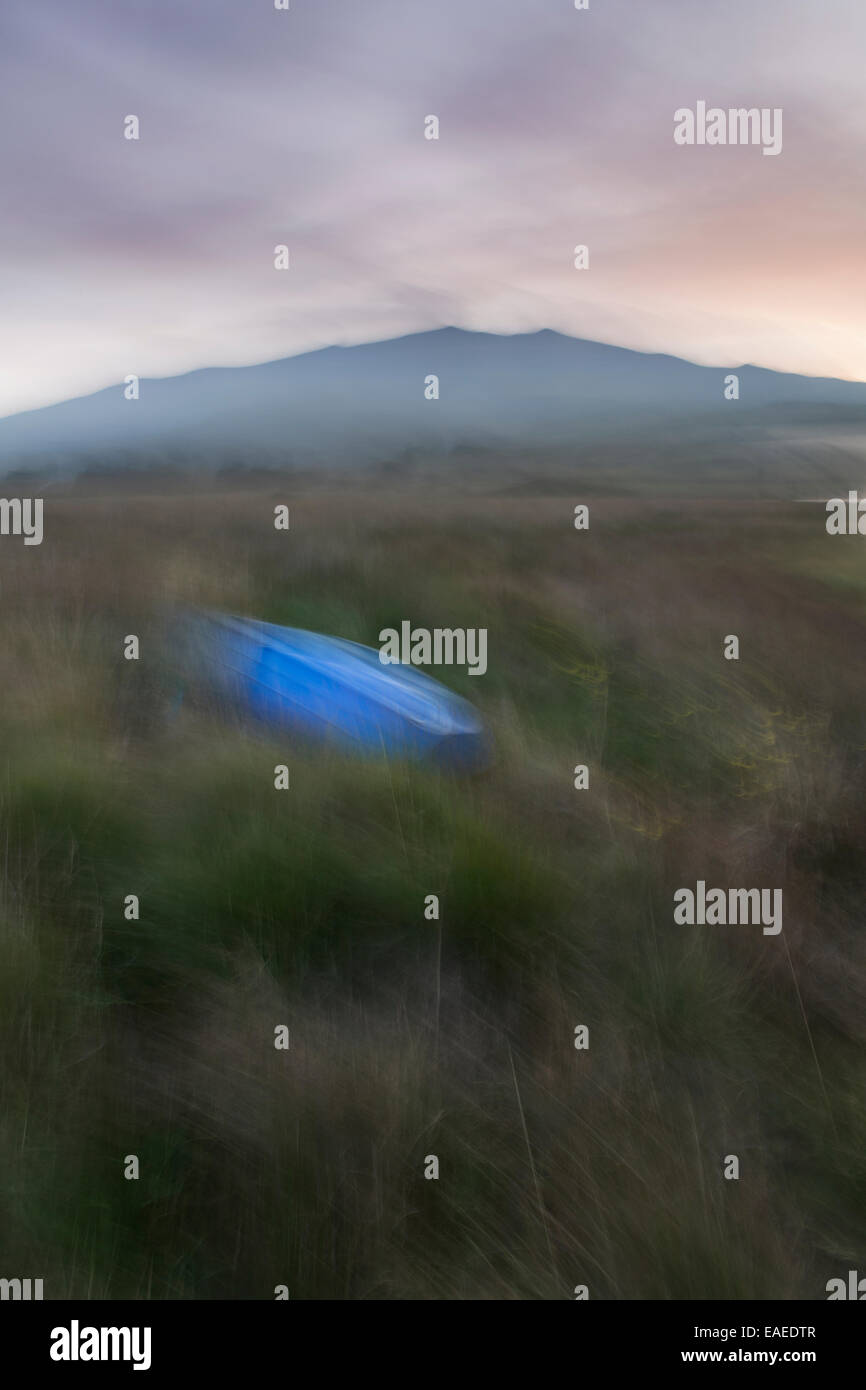 Camera movement creates an abstract image of a rowing boat on the shore ...