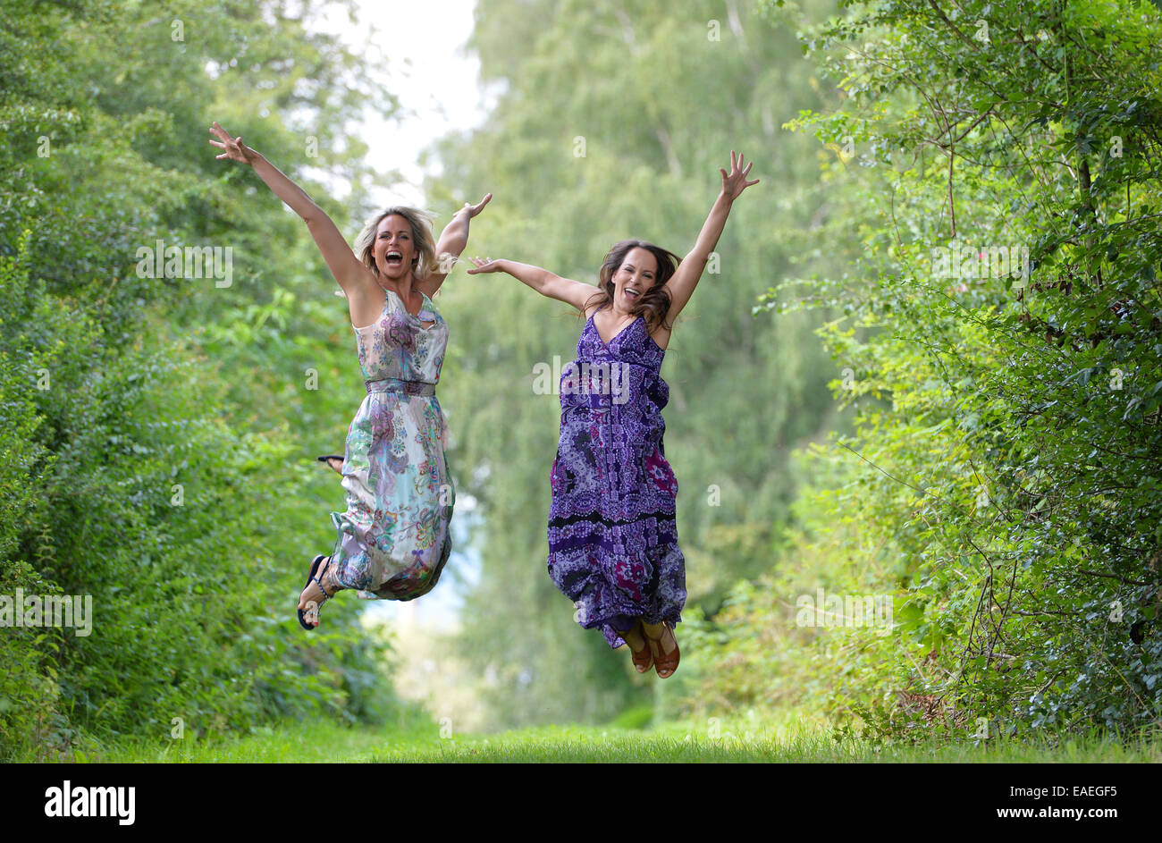Two girl friends jumping in the air joyfully Stock Photo - Alamy