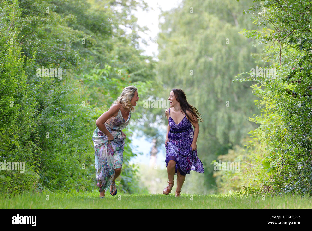 Two girl friends running joyfully along a path Stock Photo - Alamy
